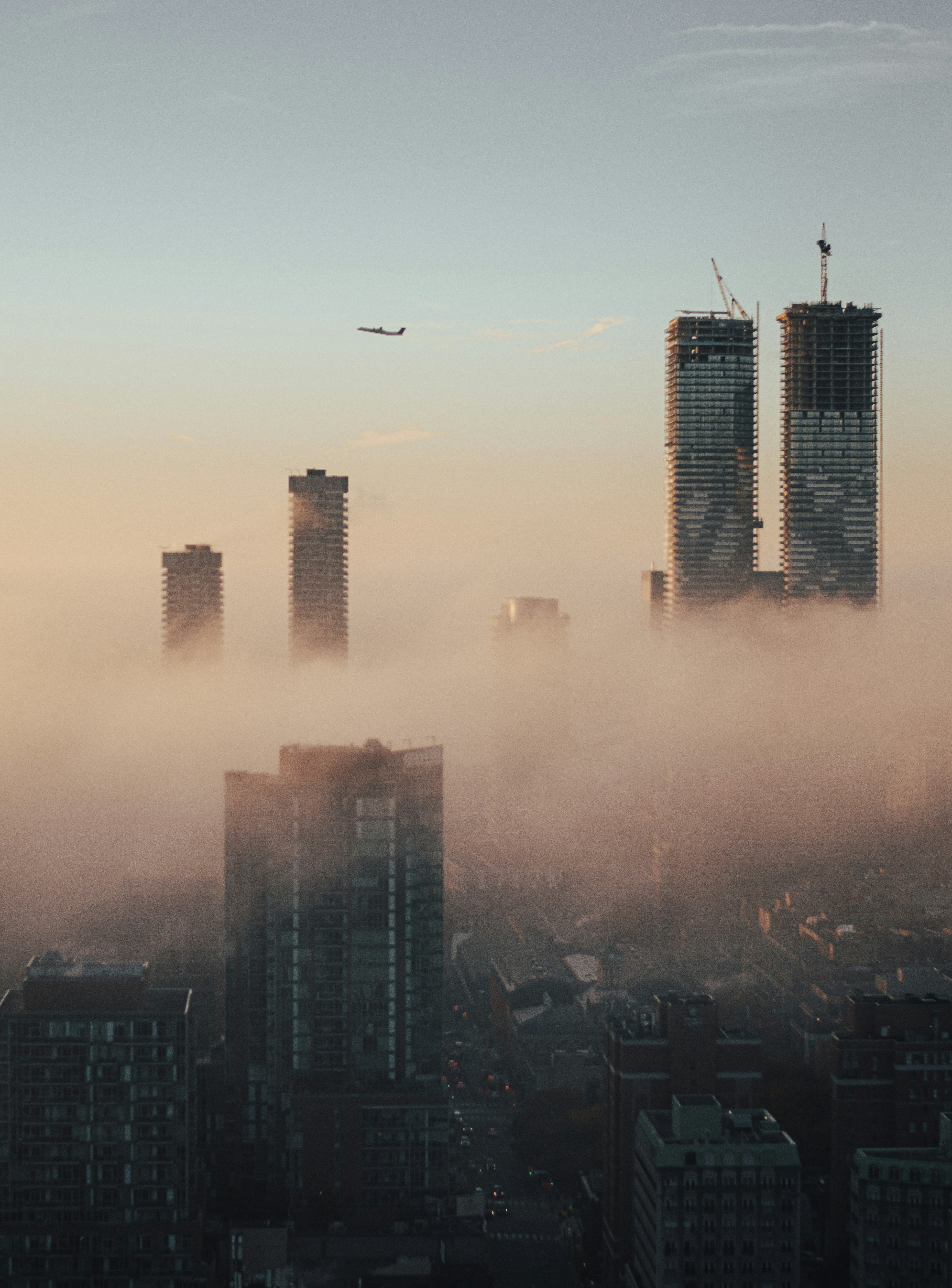 Crane-Topped Towers Awake: Dawn Light Over a Fog-Wrapped Skyline