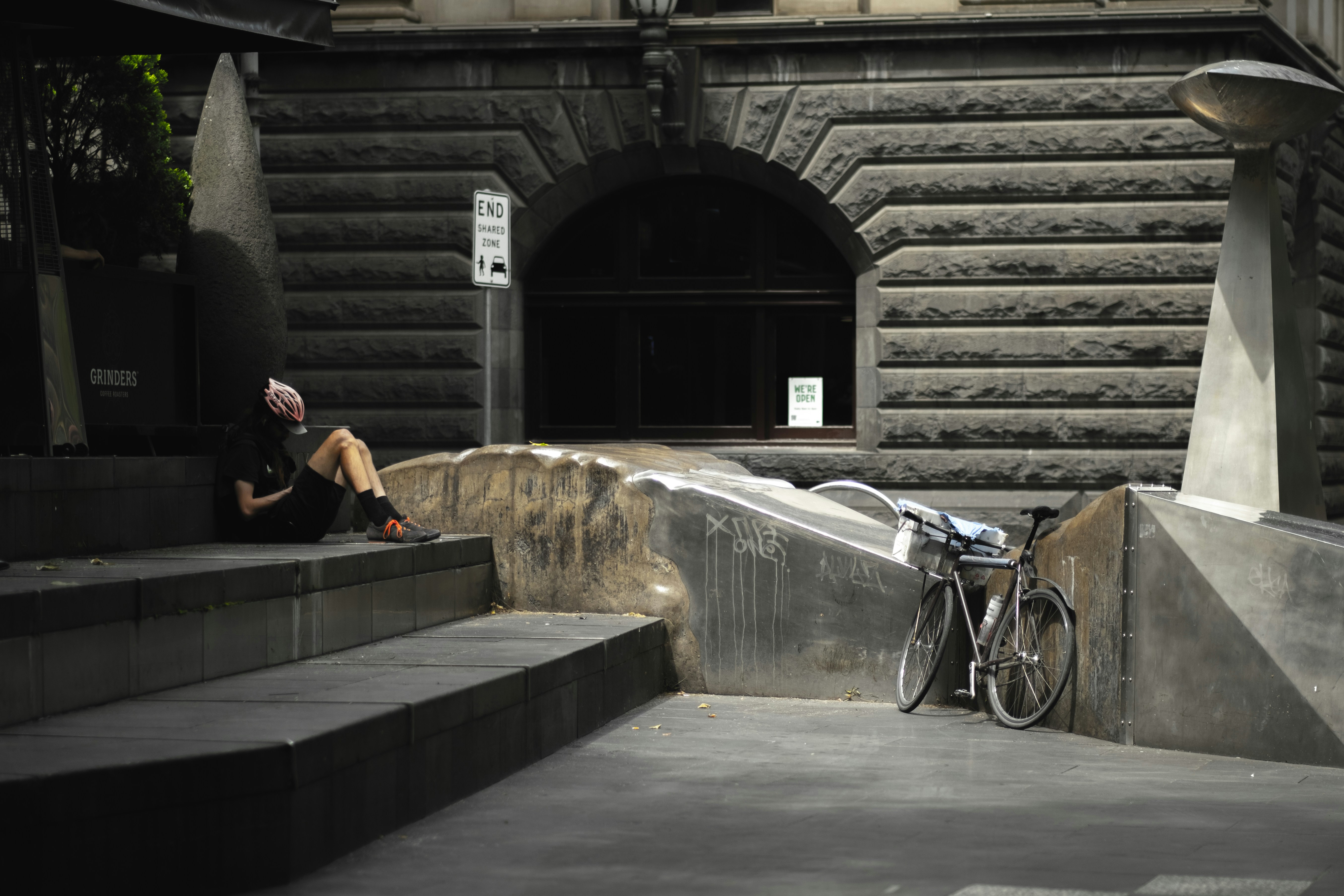 a person sitting on a stone ledge next to a bicycle