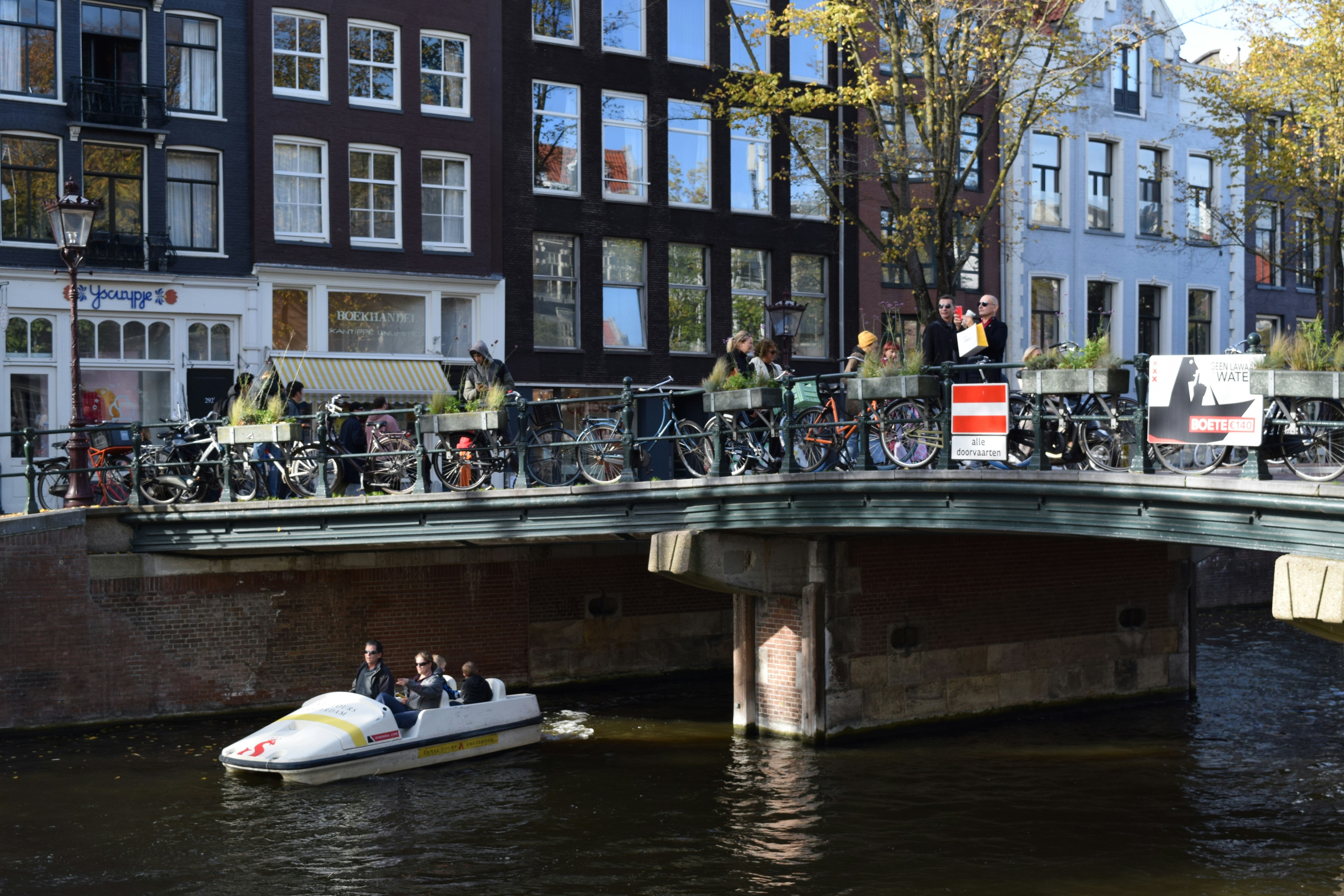 Amsterdam Canal Pulse: White Motorboat Beneath a Bicycle-Laden Bridge