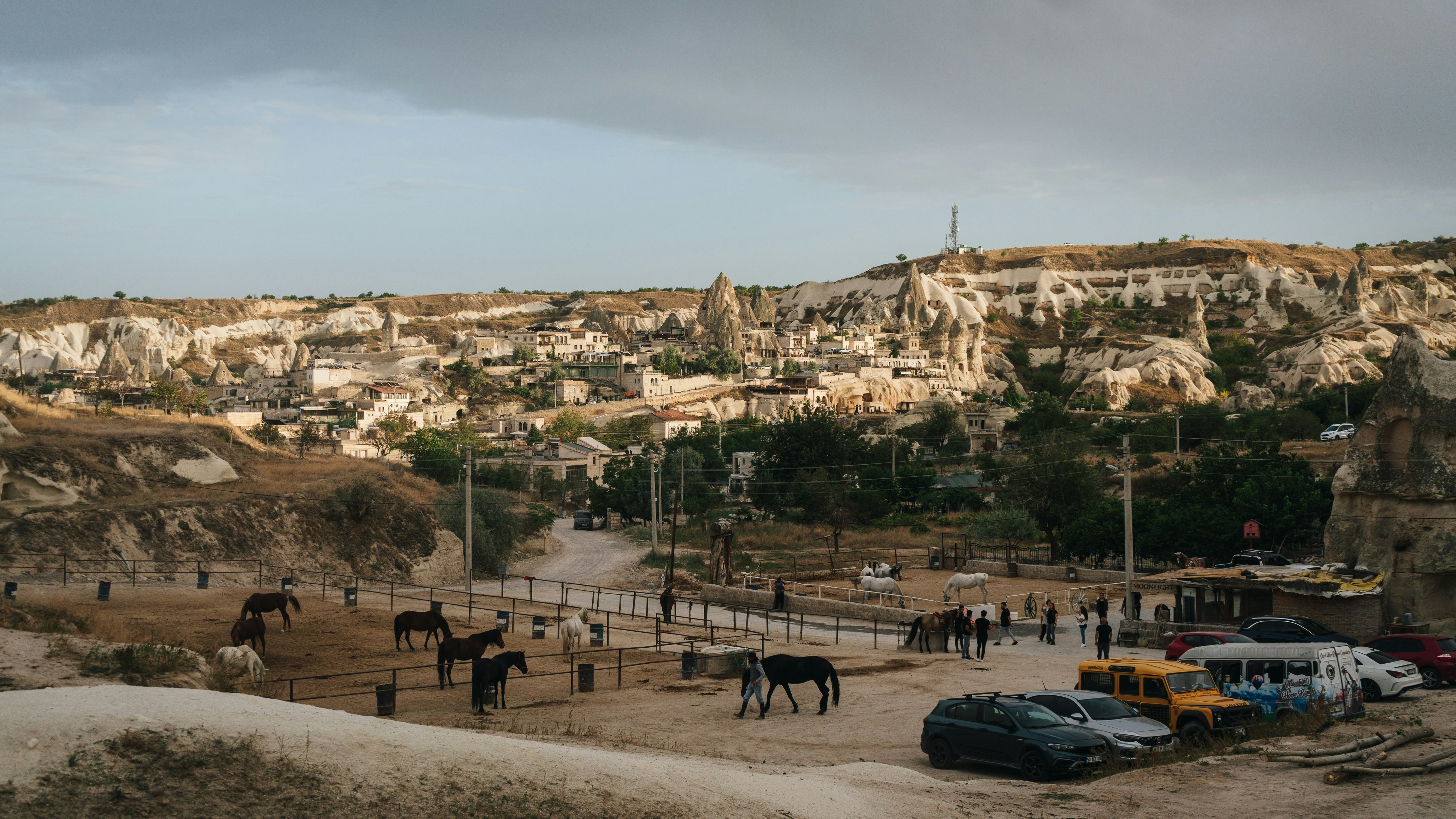 Hilltop Stables: A Caravan of Horses and Vehicles Beneath an Ancient Ridge