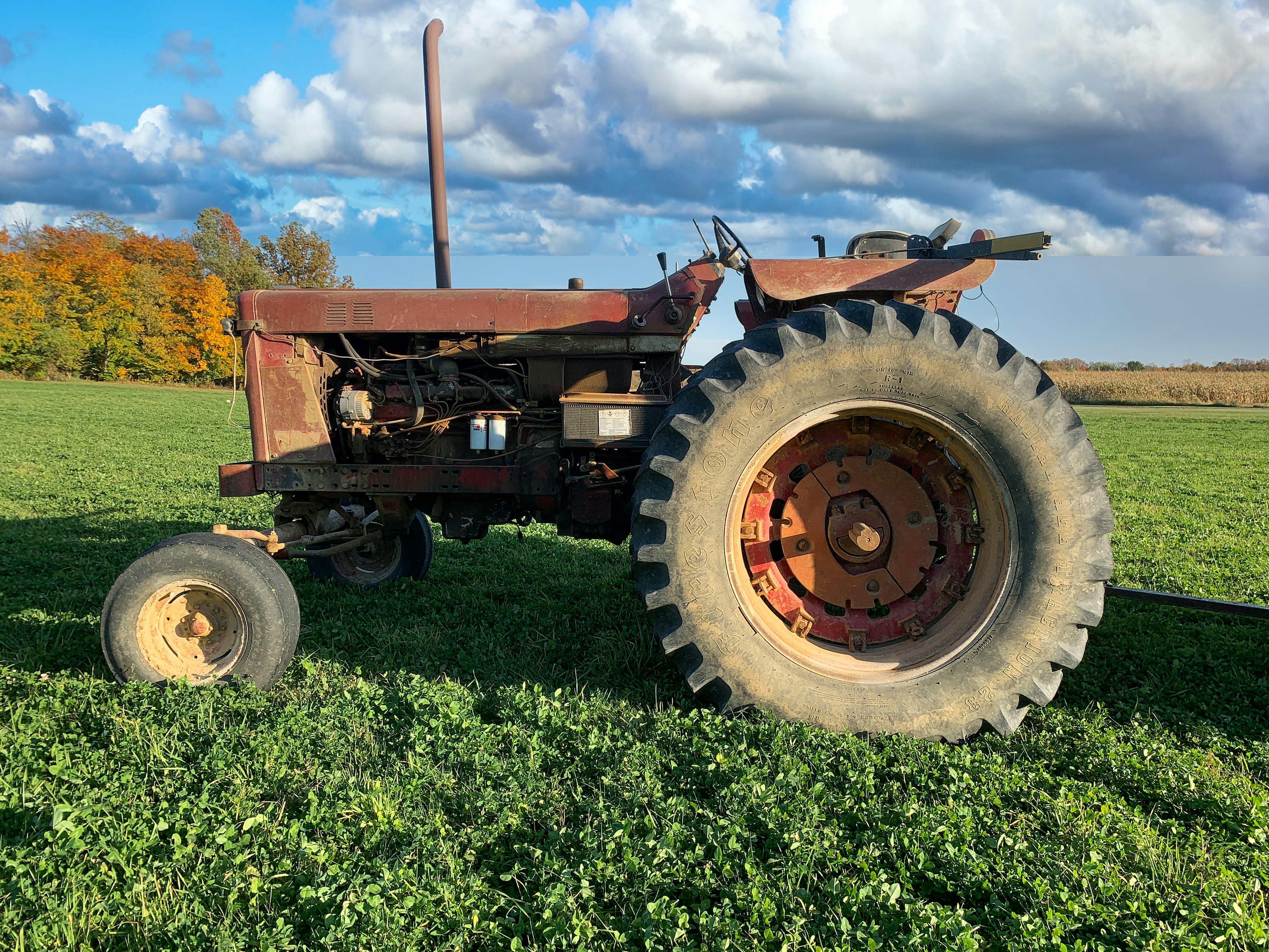 Rust and Red in a Quiet Field: A Weathered Tractor Under a Cloudy Sky