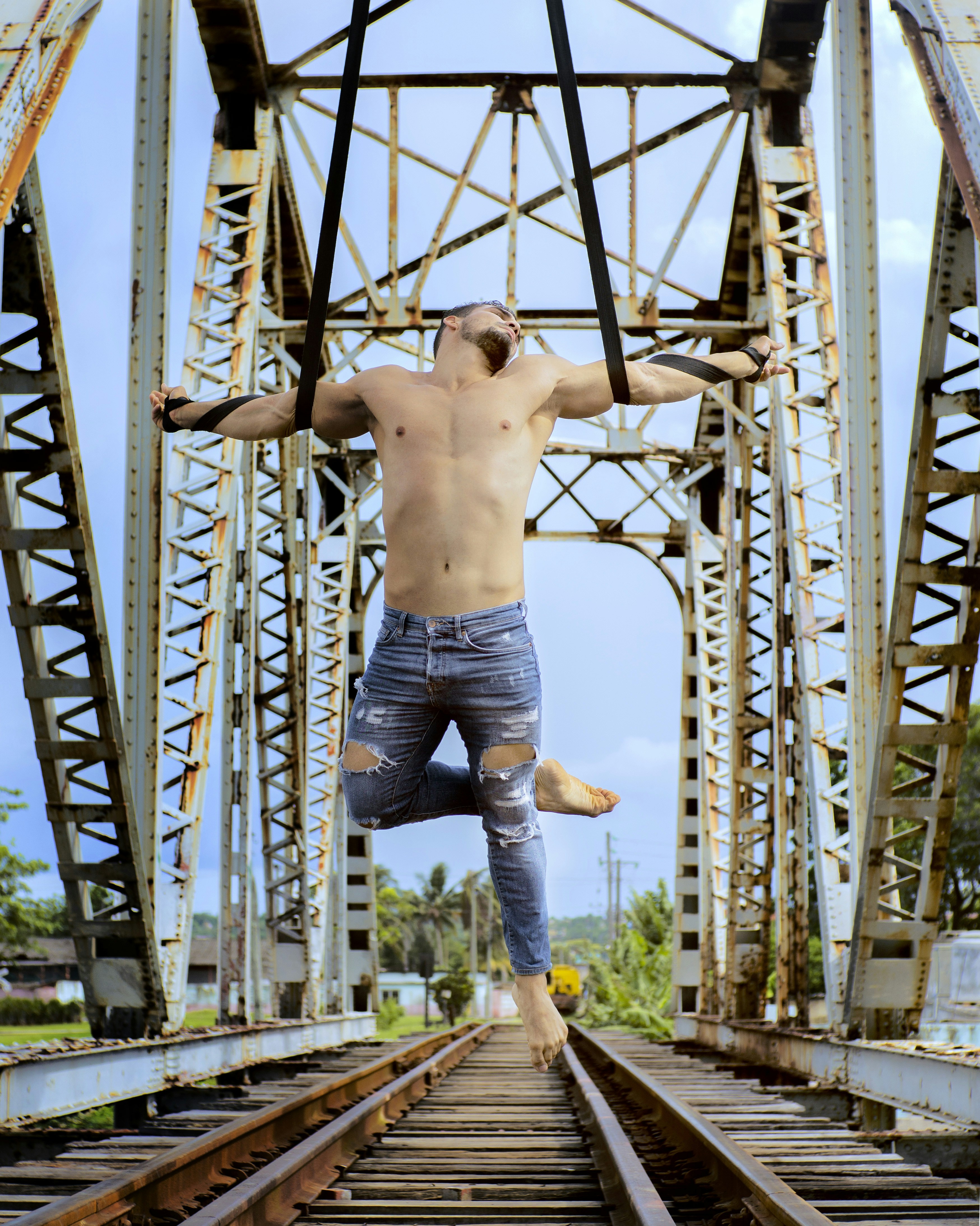Midair on the Rails: A Shirtless Leap Under Rusted Trusses