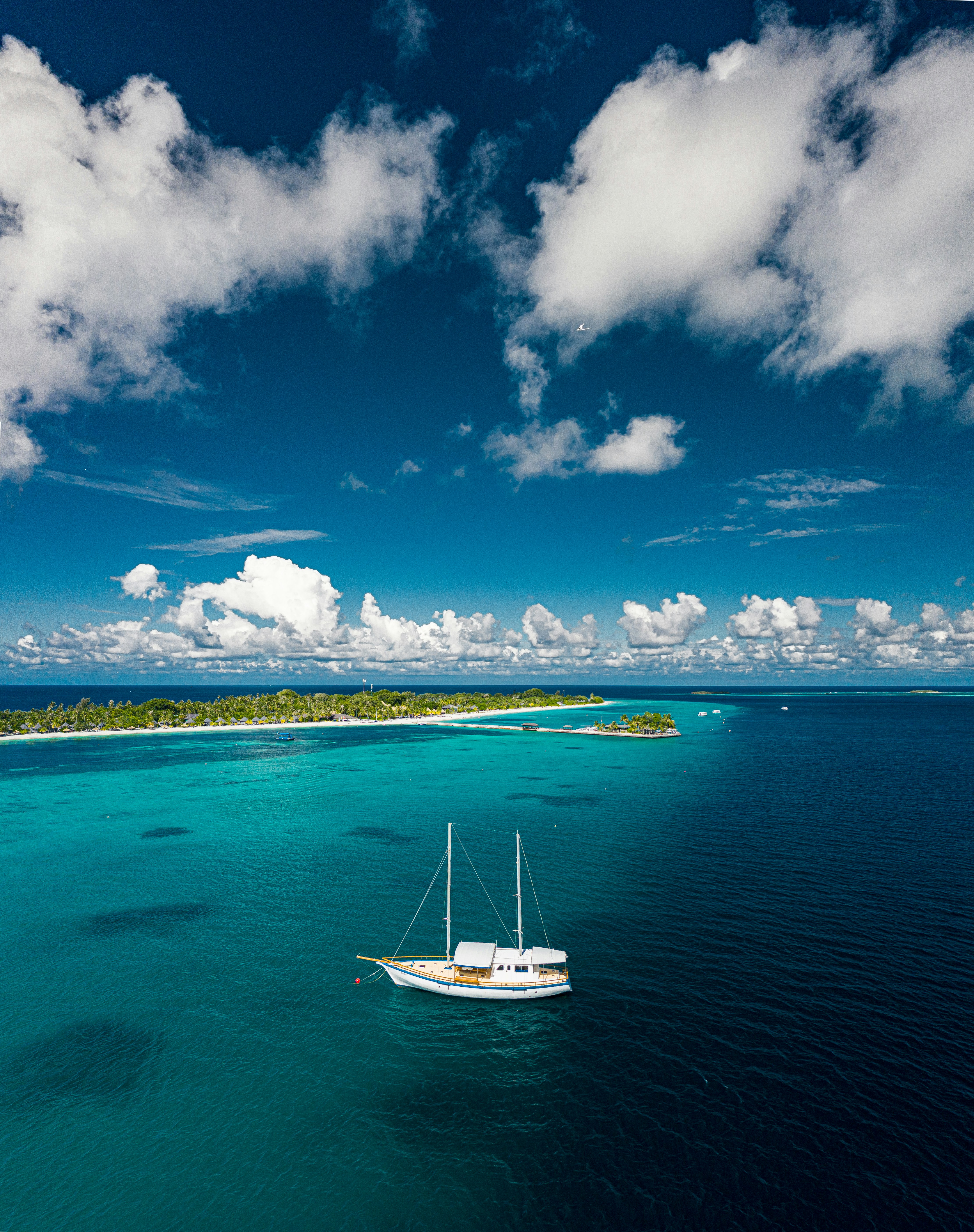 Sapphire Seas: A lone sailboat adrift over turquoise lagoon