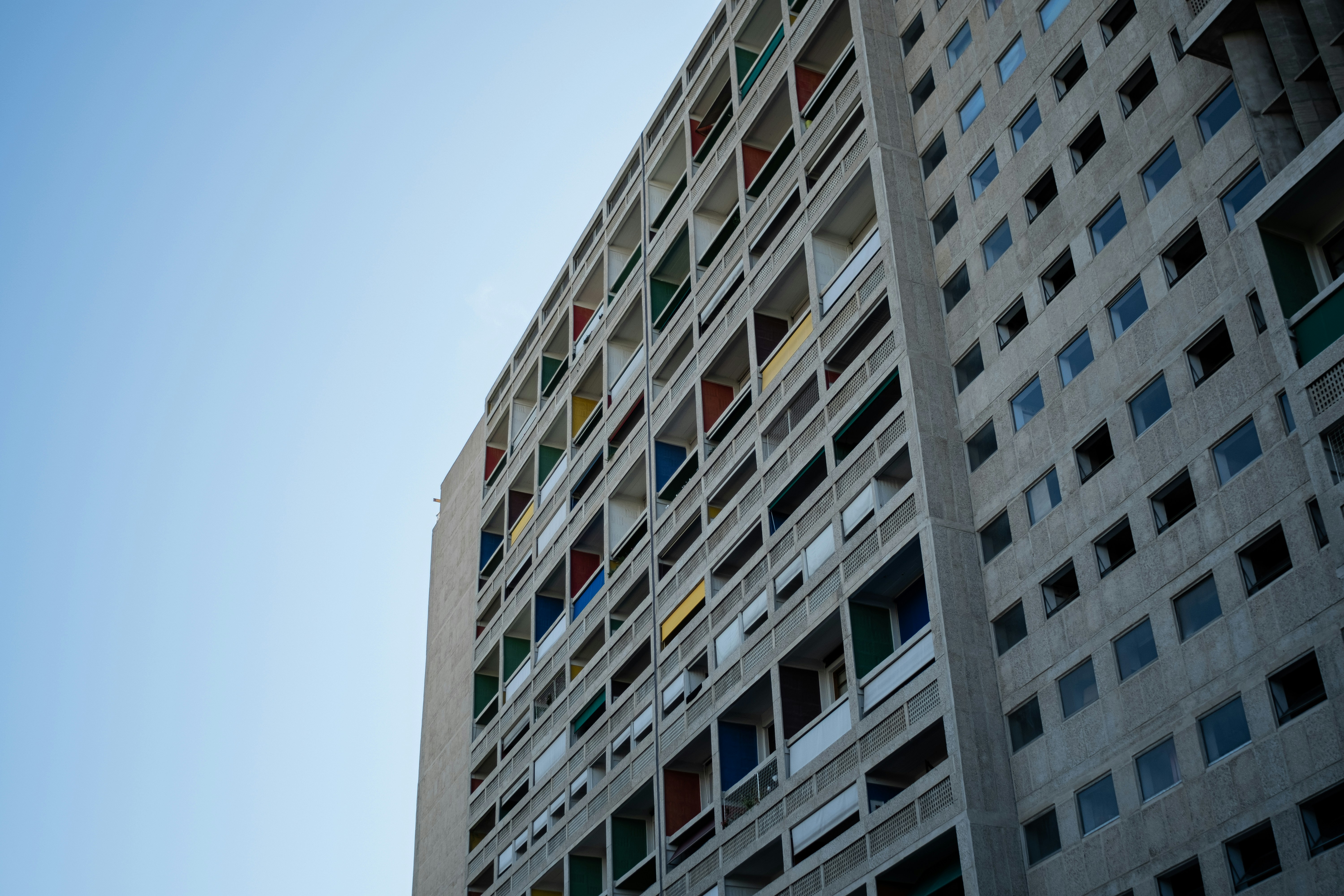 High-rise building with colorful window accents against a clear blue sky.