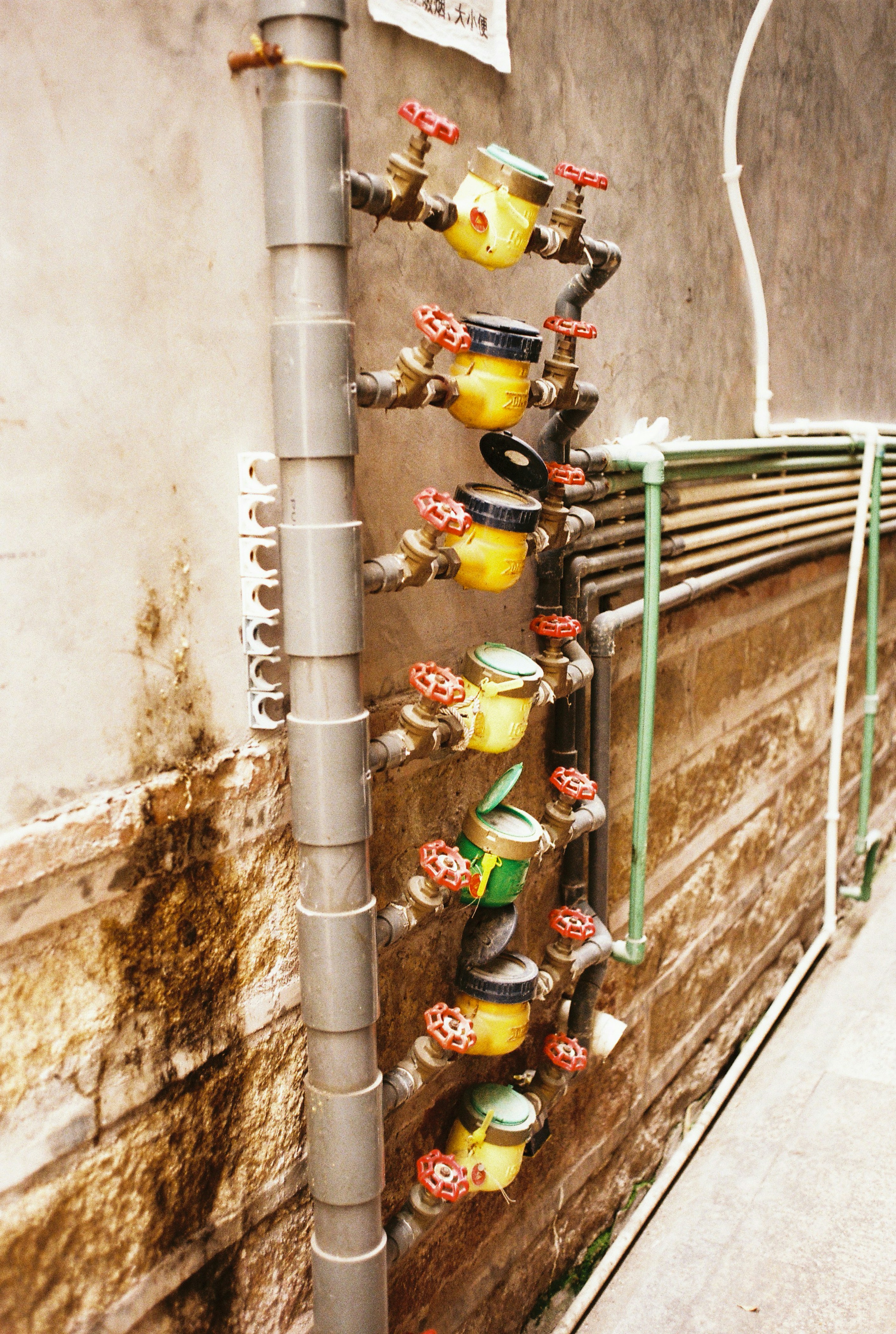 A series of vibrant water meters attached to a gray wall, showcasing a blend of industrial functionality and artistic flair.