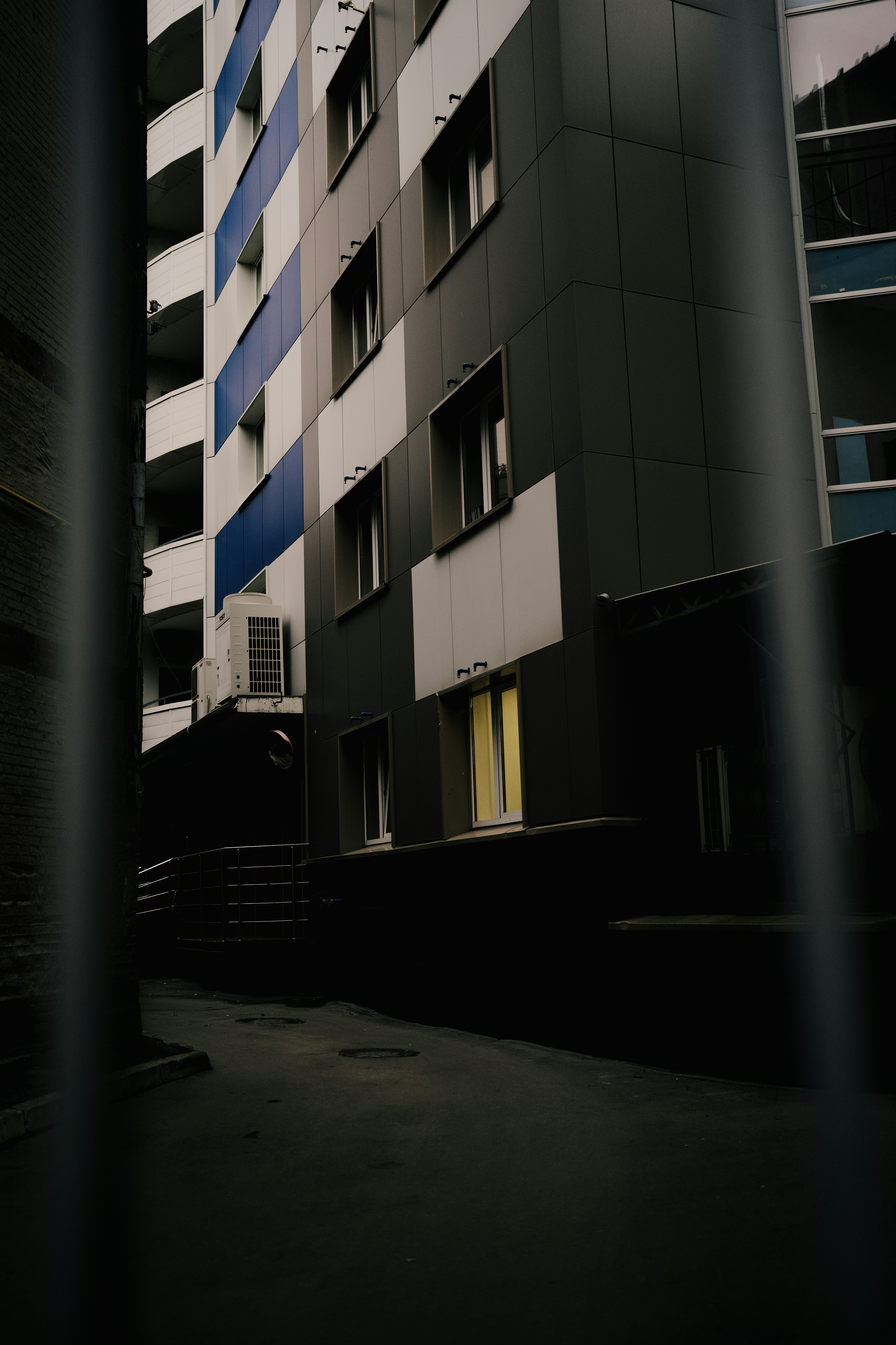 Through the Grille: A Warm Window in a Monochrome Block