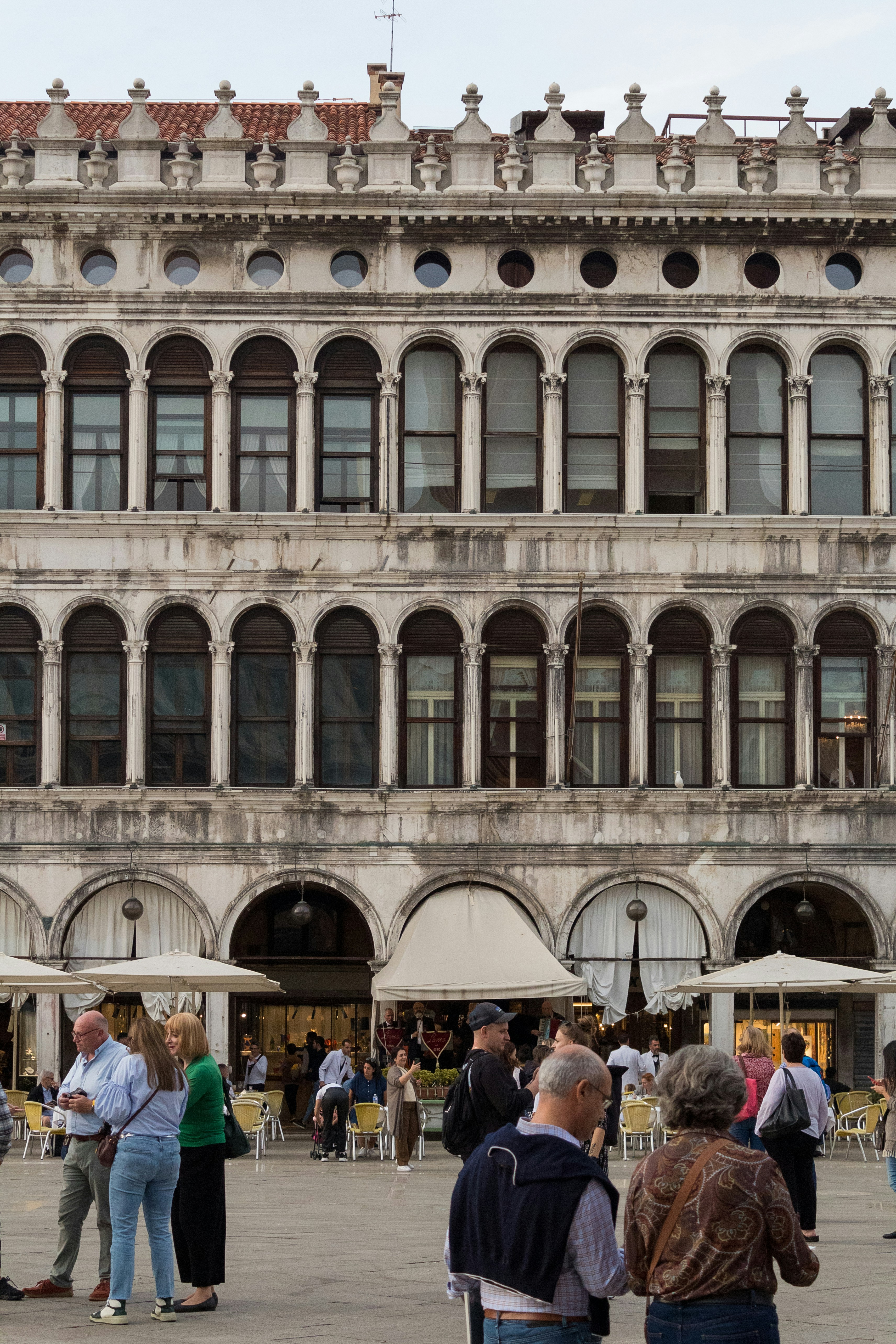 Arcaded Facade: Sunlit Arches Over a Bustling Piazza