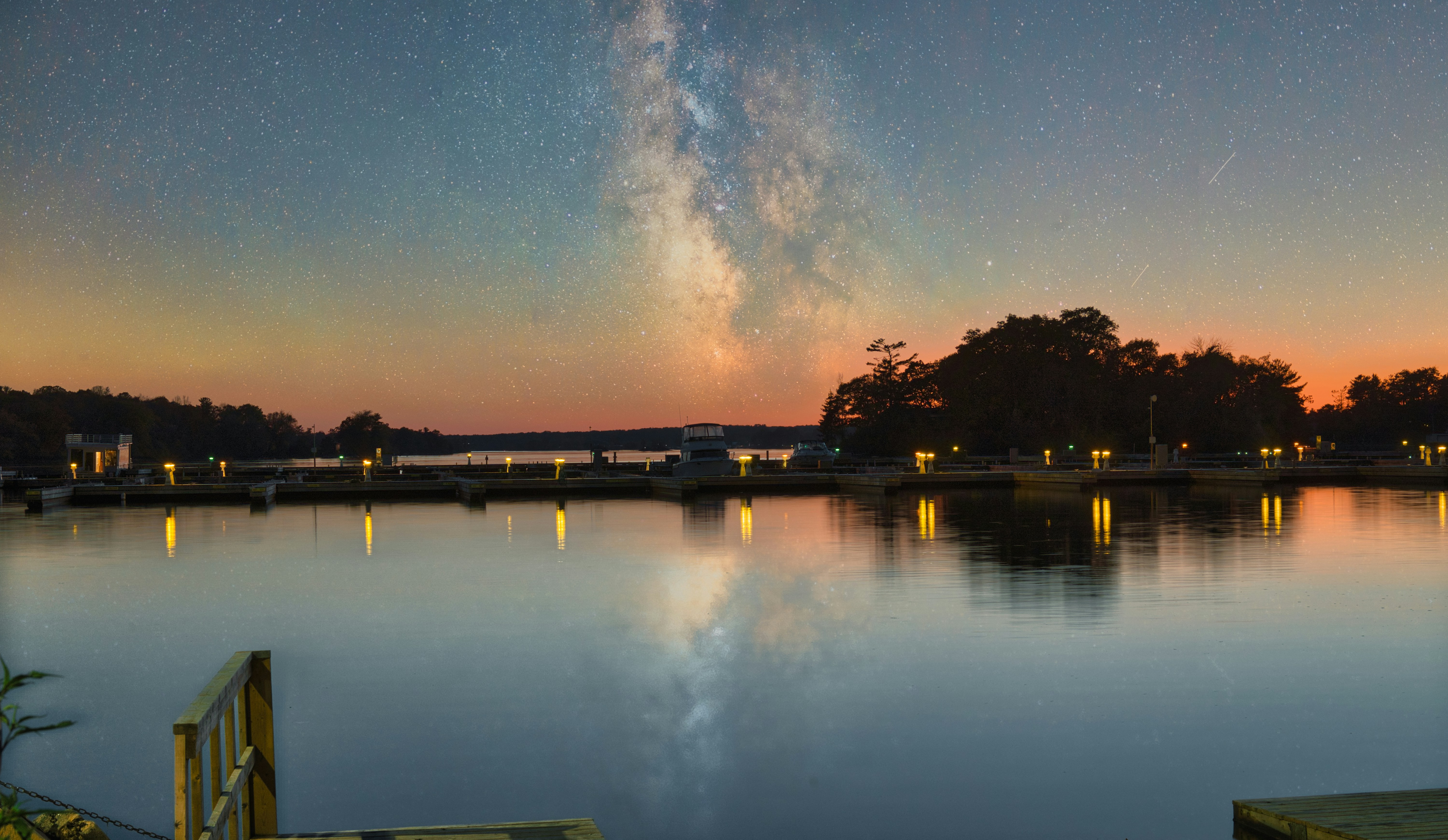 Milky Way Over a Tranquil Lakeside Pier with Lantern-lit Reflections