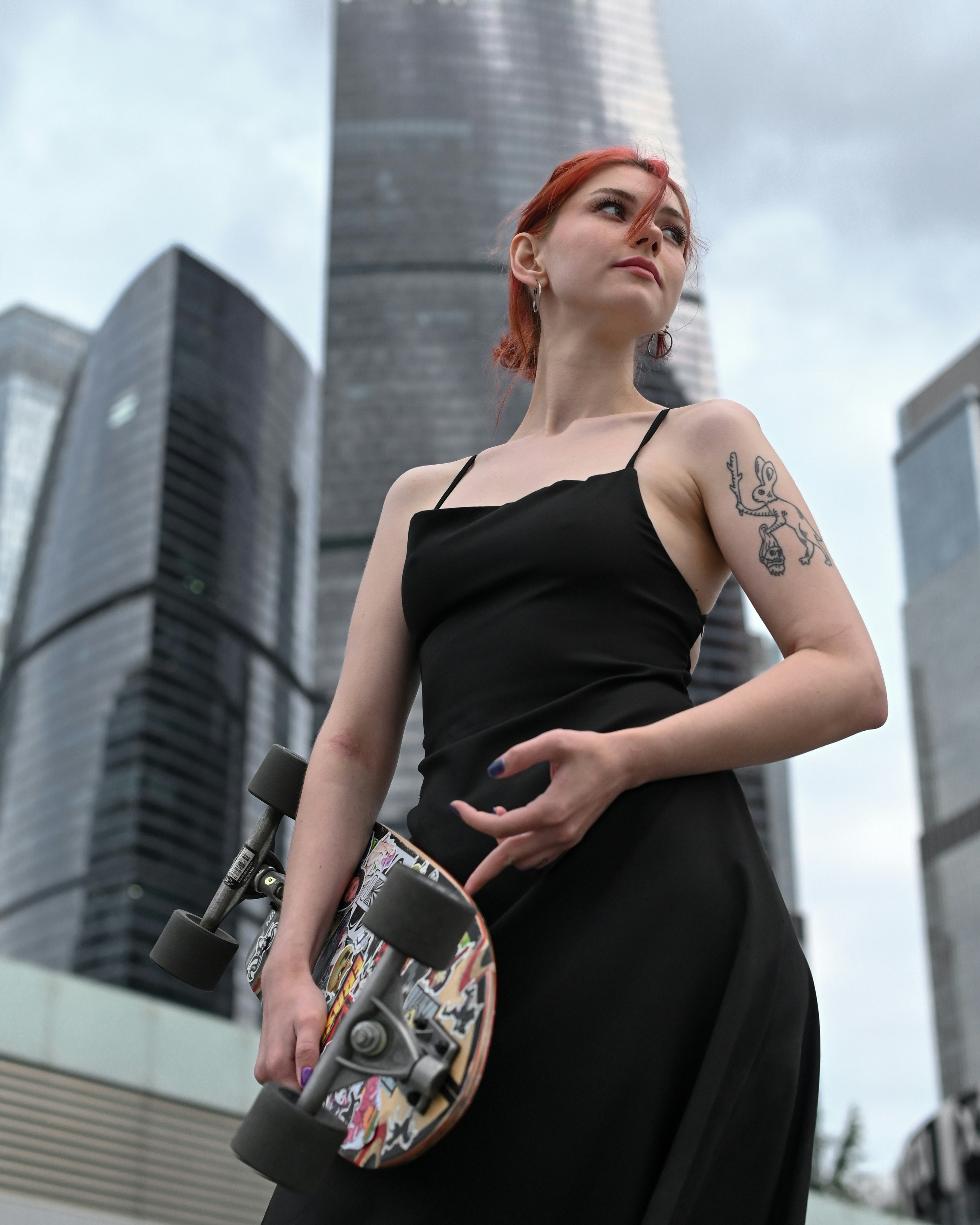 Red Hair, Glass Canopy: A Skateboarder Stands Bold in the City