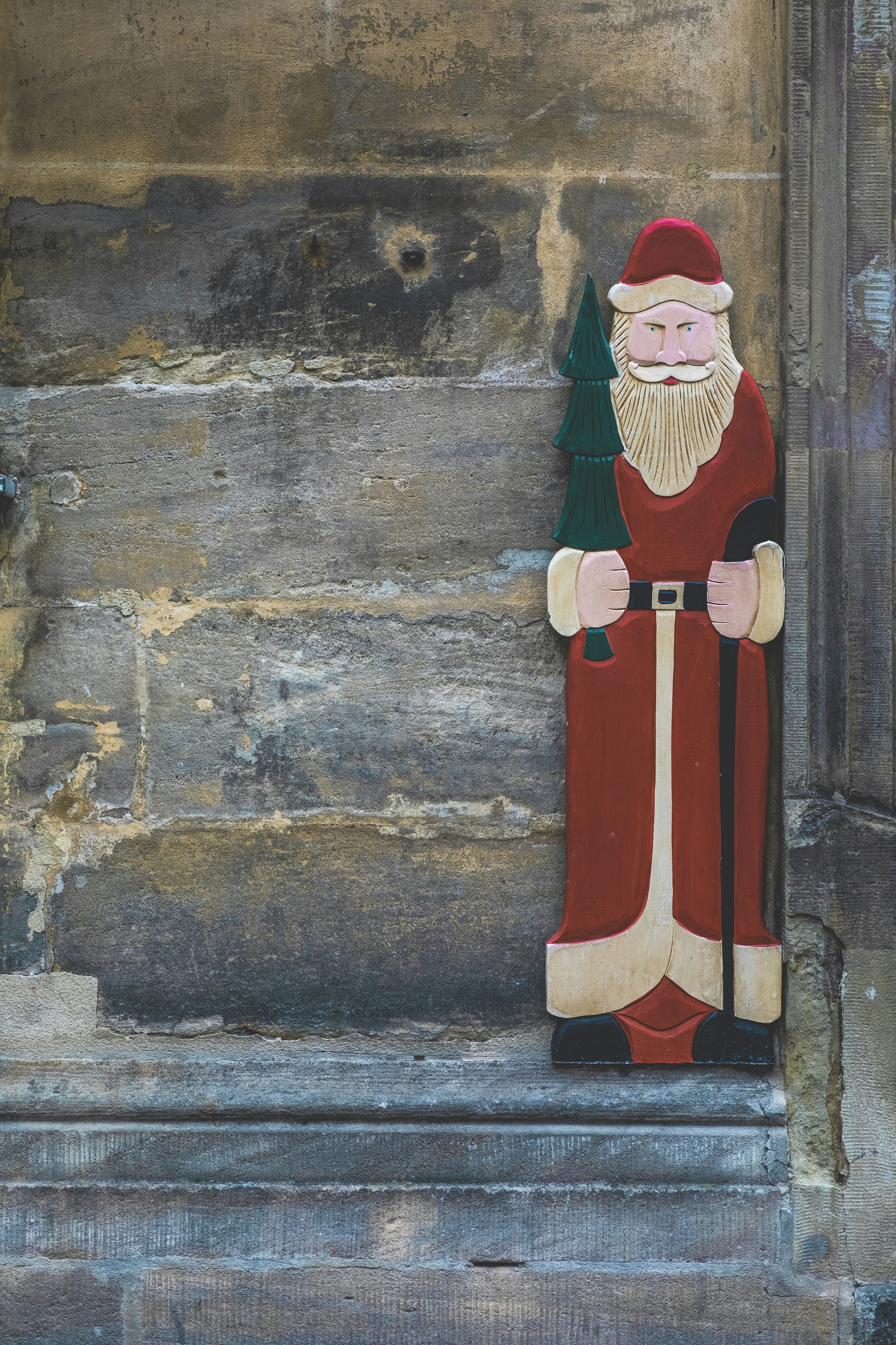 Wooden Santa by the Doorstep: A Seasonal Cutout on a Weathered Wall