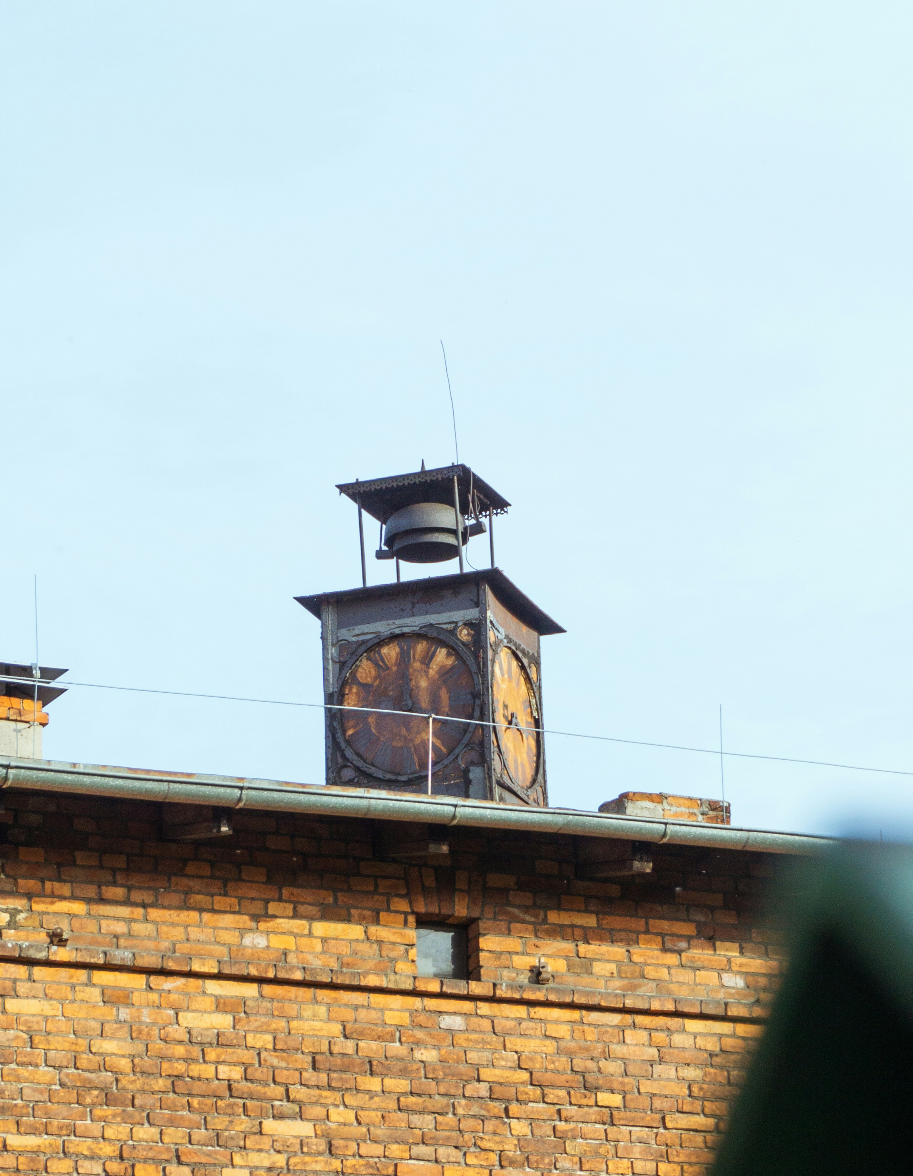 Clock Tower Rising from a Brick Rooftop Beneath a Pale Sky