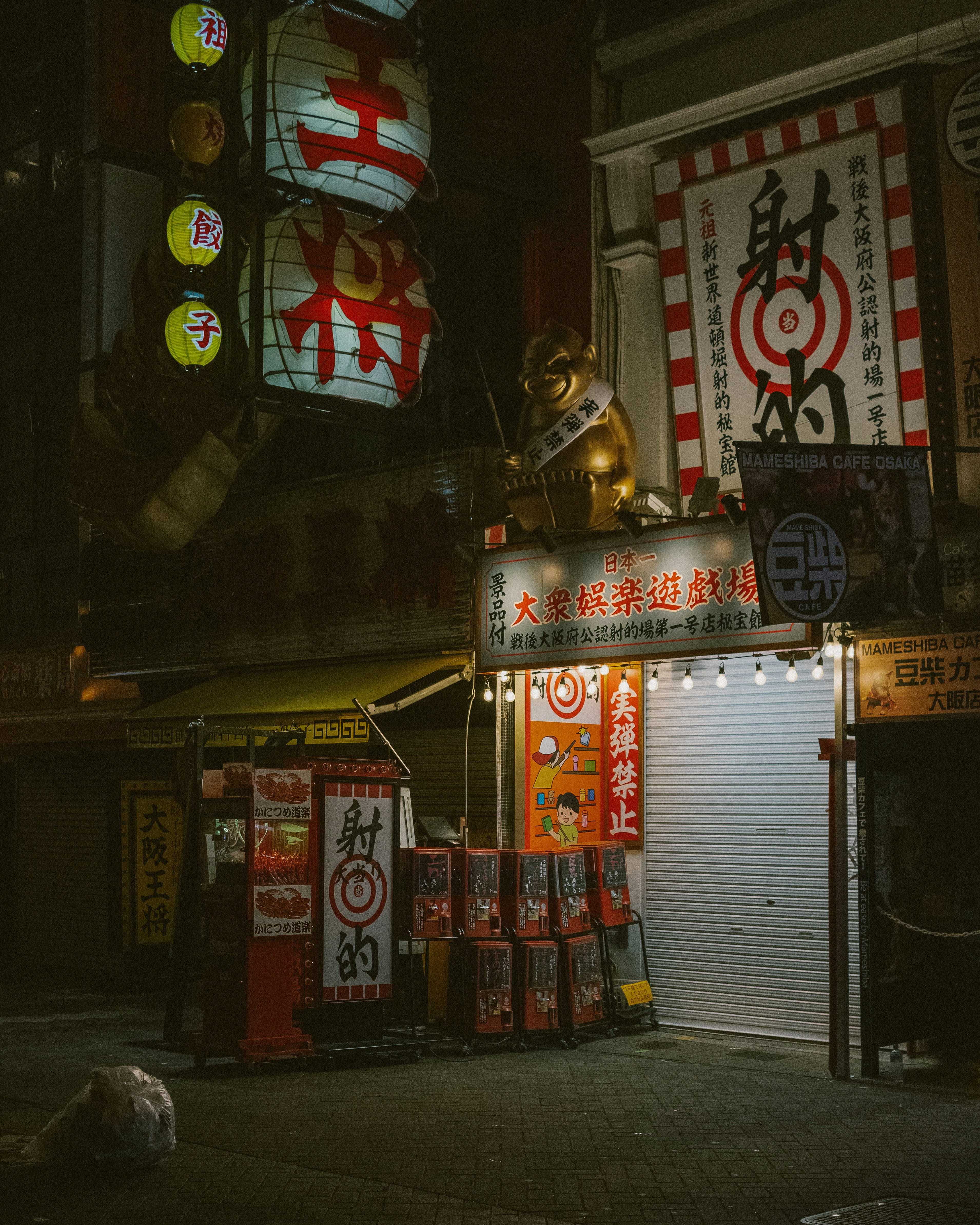 Vibrant storefront adorned with neon signs and a golden bear statue, capturing the essence of Osaka's bustling entertainment scene.