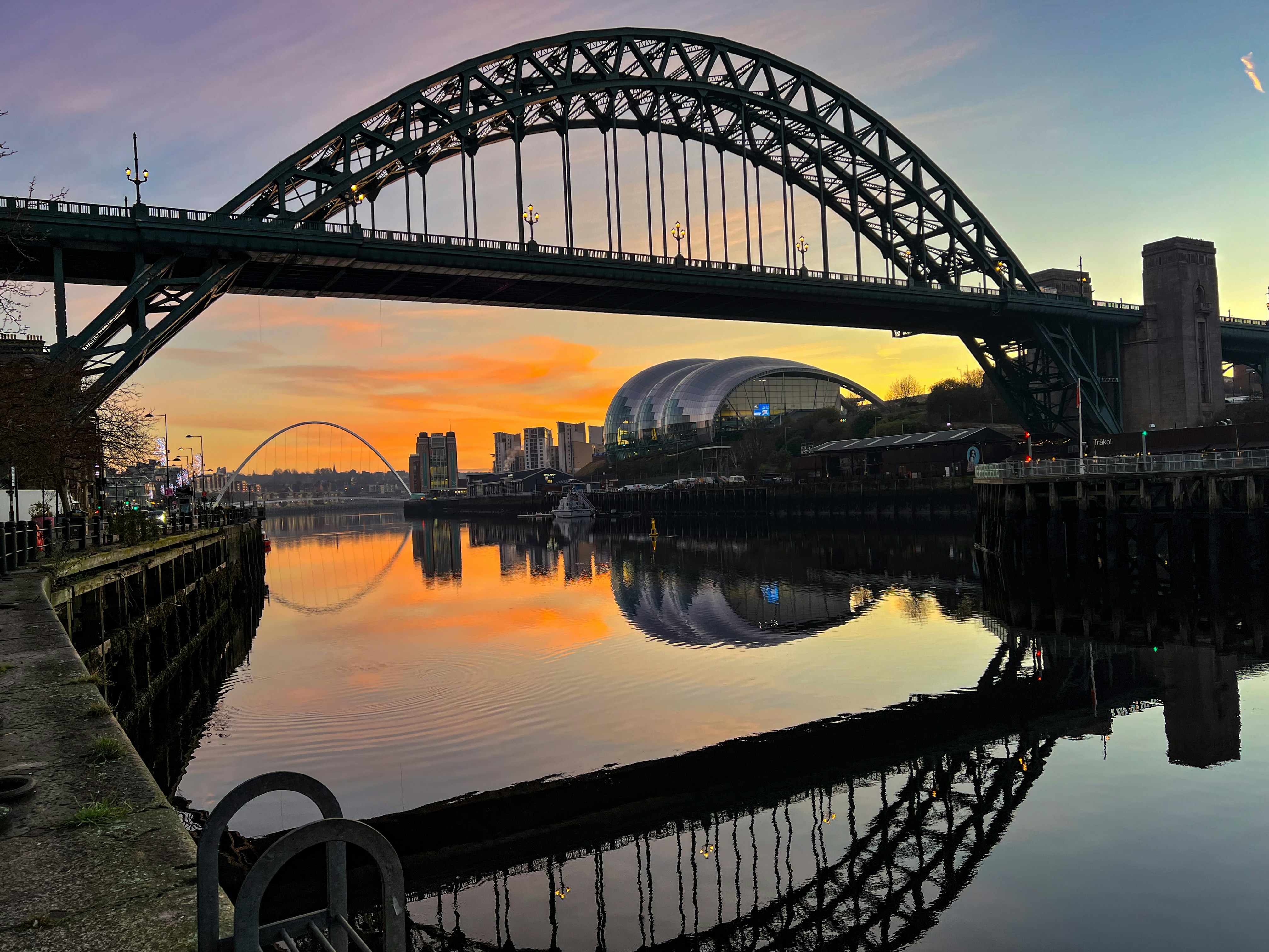 The Tyne Bridge in Newcastle at sunrise on a wintery morning in January | a bridge over water with a city in the background