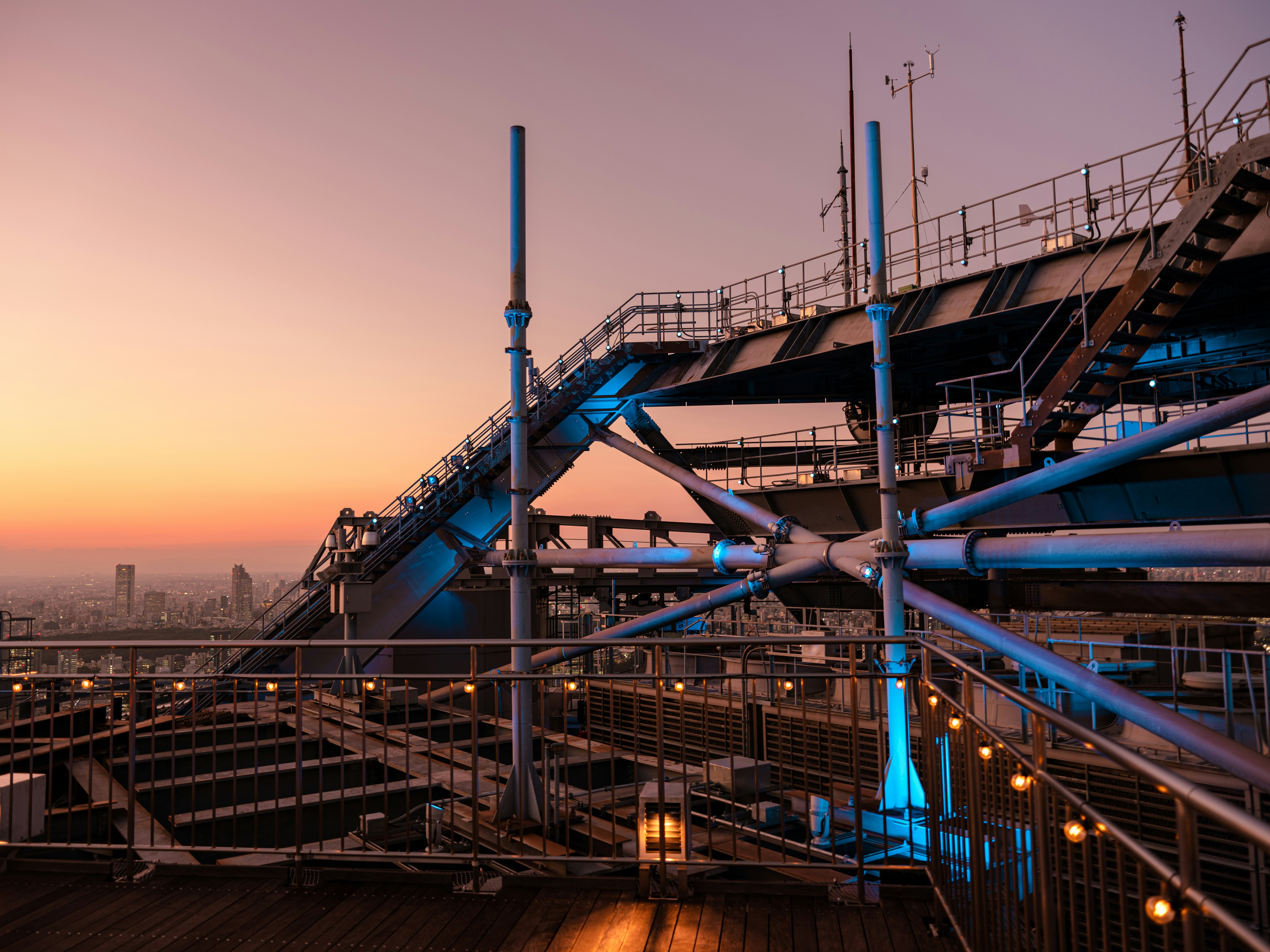 Rooftop Framework at Dusk: Blue Steel Structures Against a City Glow