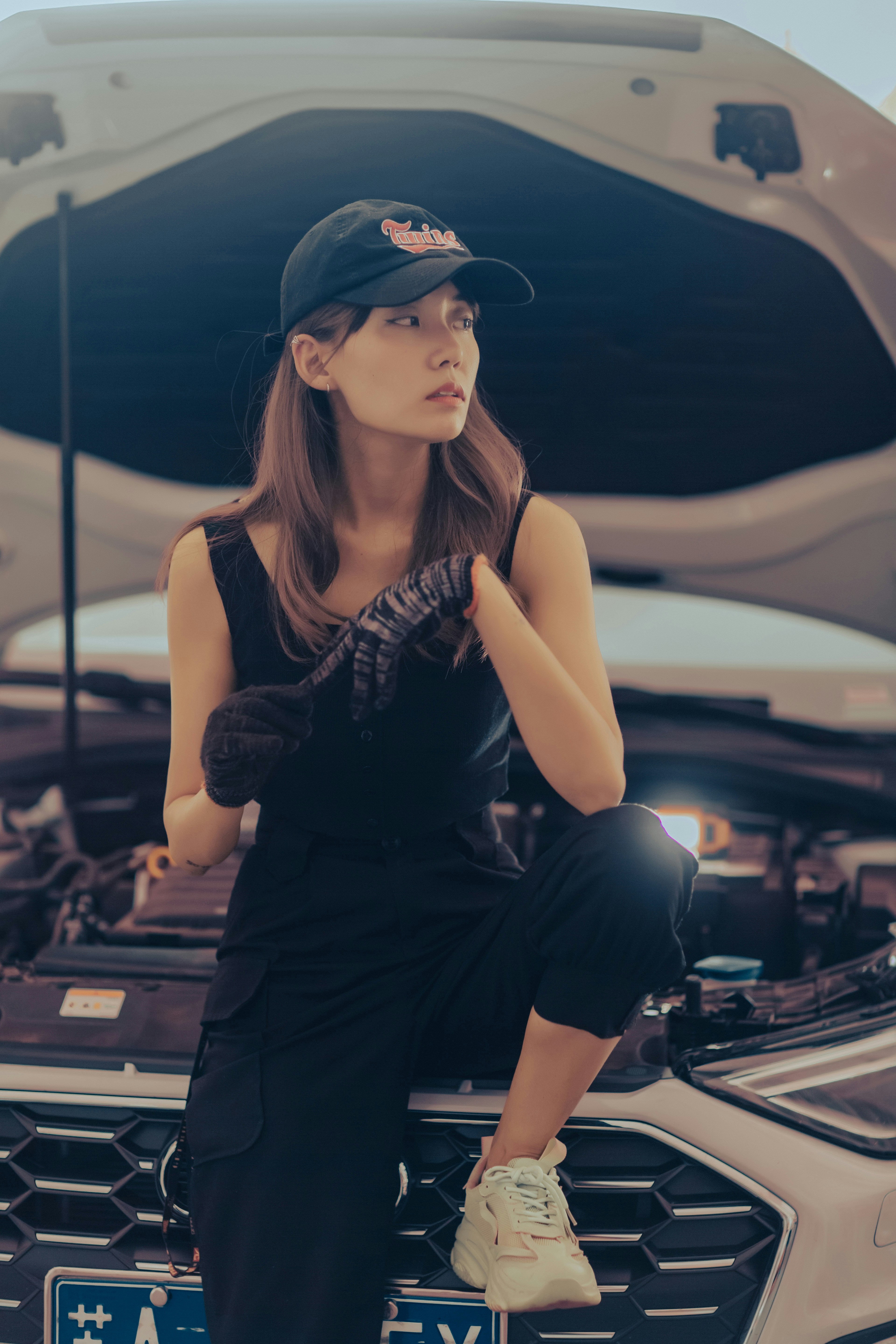 a woman in a black dress and hat sitting on a vehicle