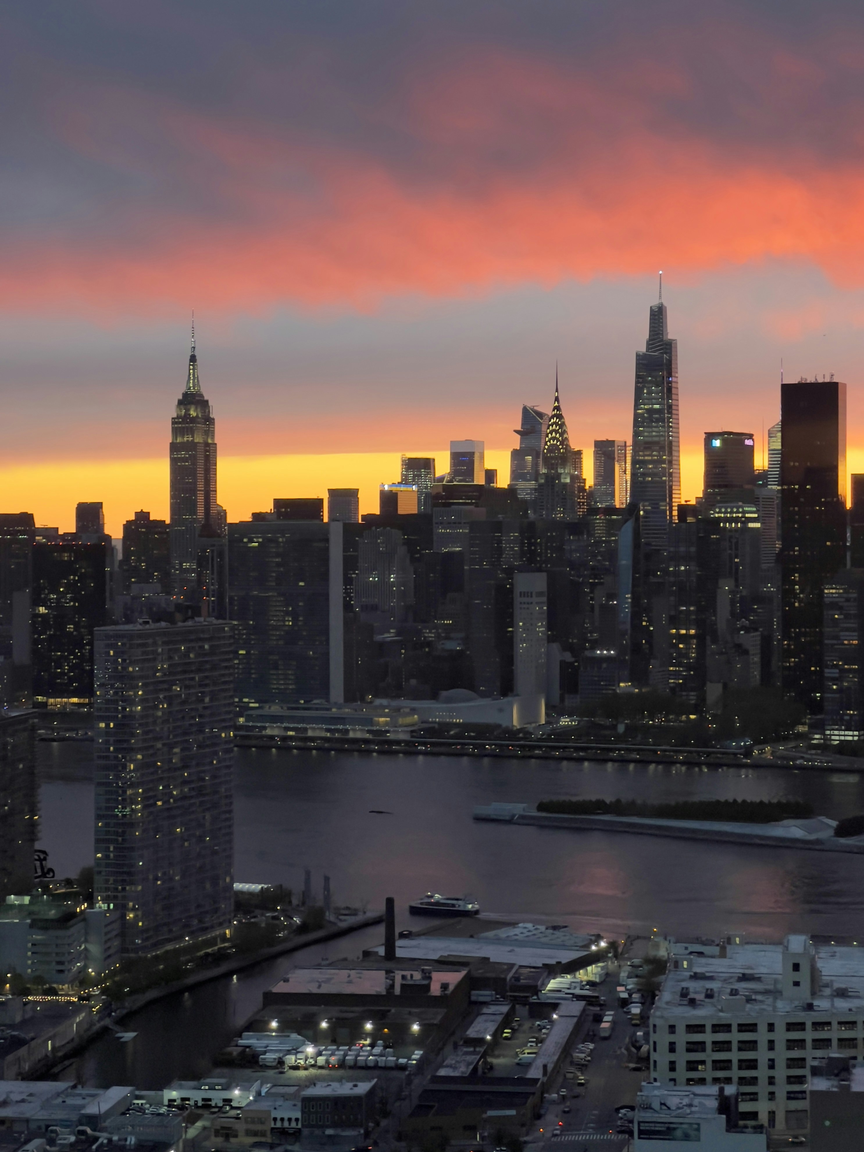New York City skyline with glowing sunset hues highlighting skyscrapers across the river.
