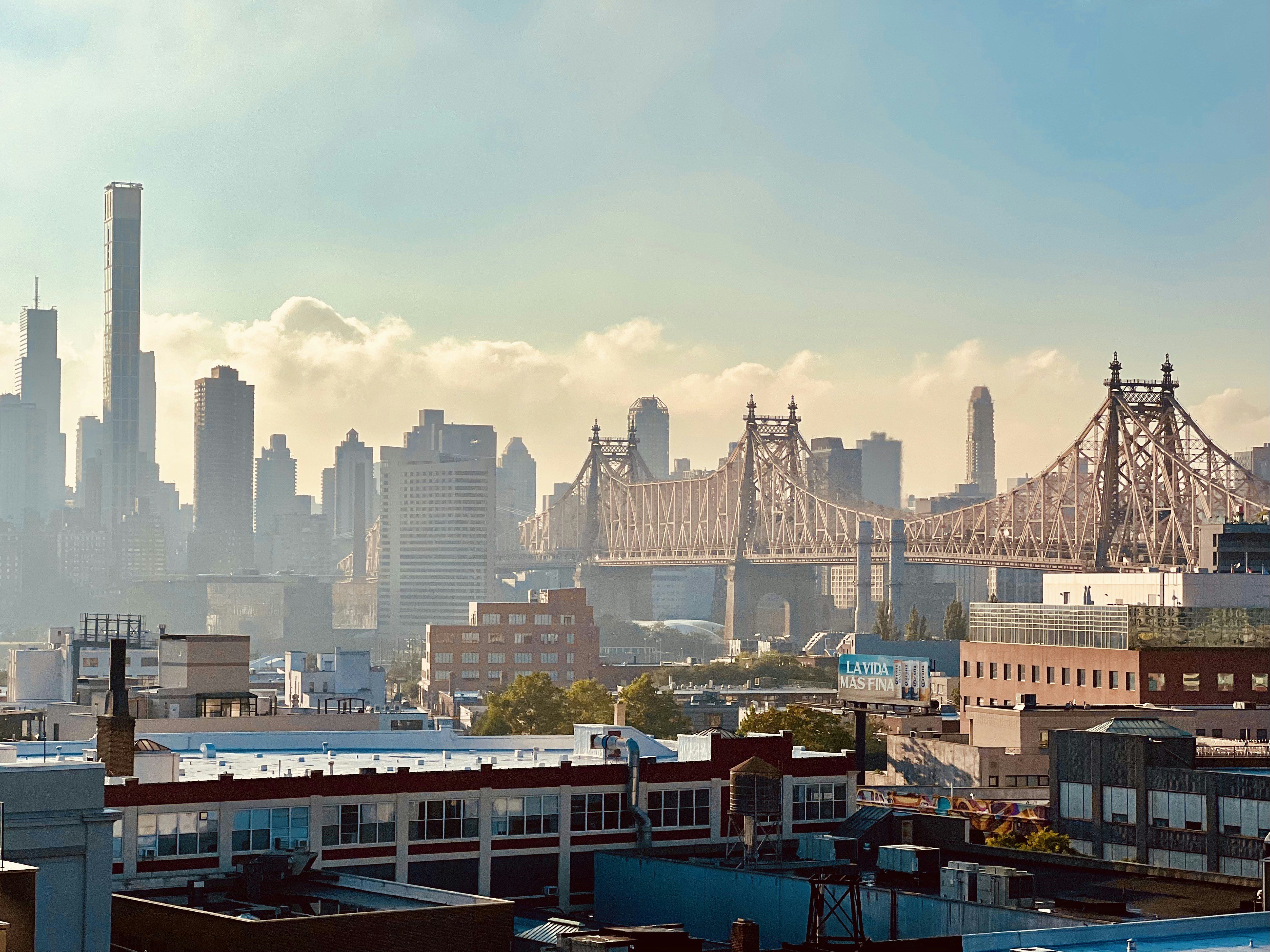 Skyline of Long Island City with the Queensboro Bridge under a hazy afternoon sky.