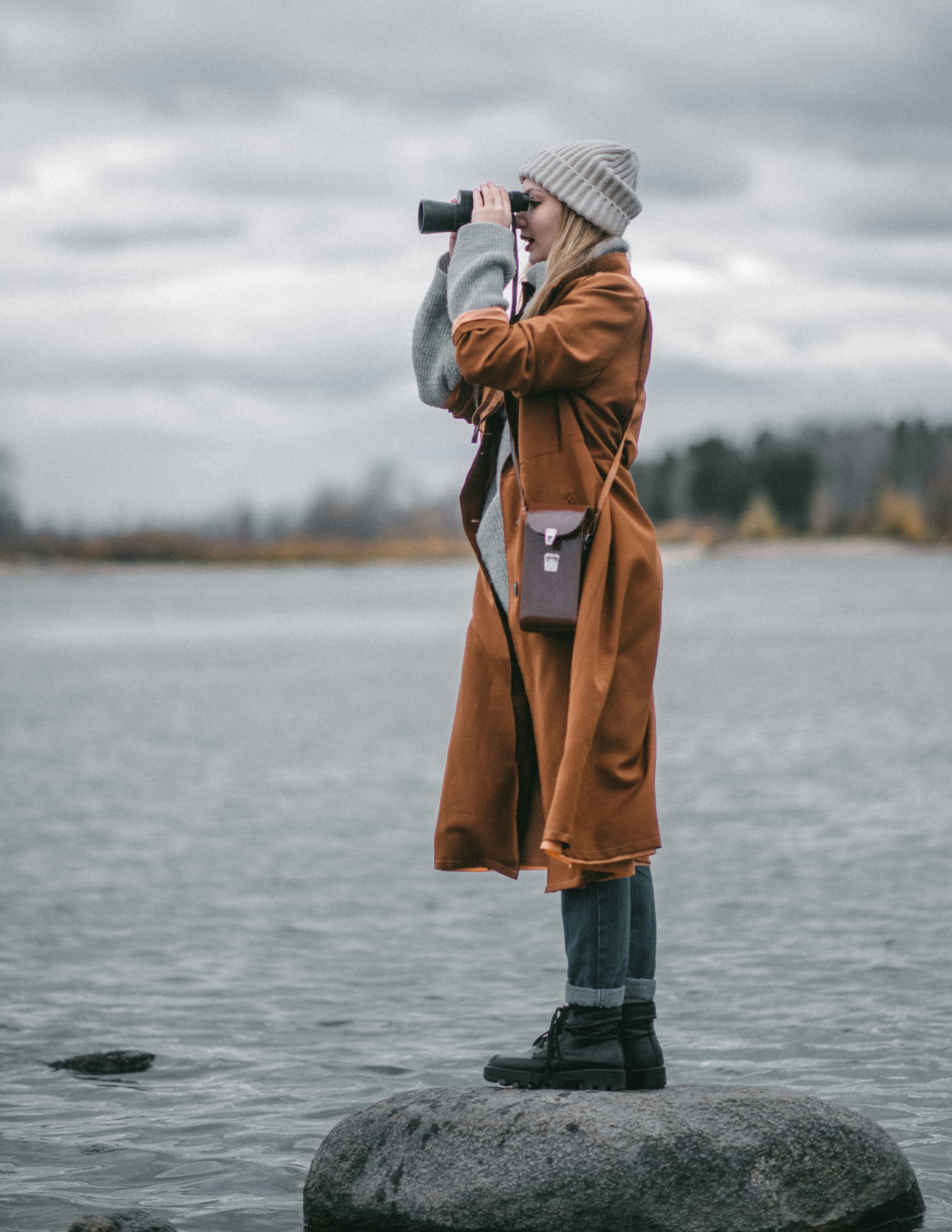 a person with a camera on a rock by water