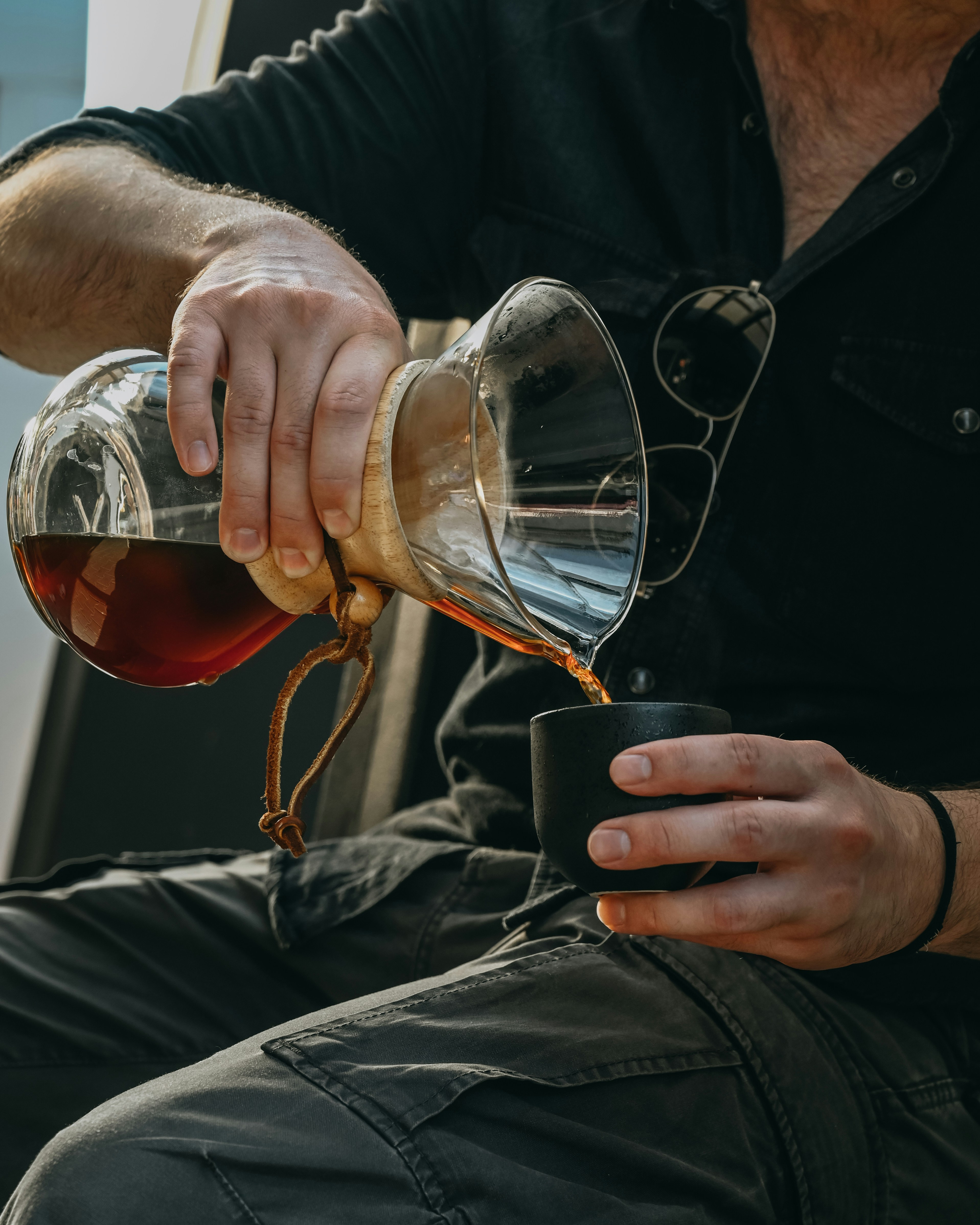 Pouring ritual: amber coffee and wine-like stream in a sunlit pour-over