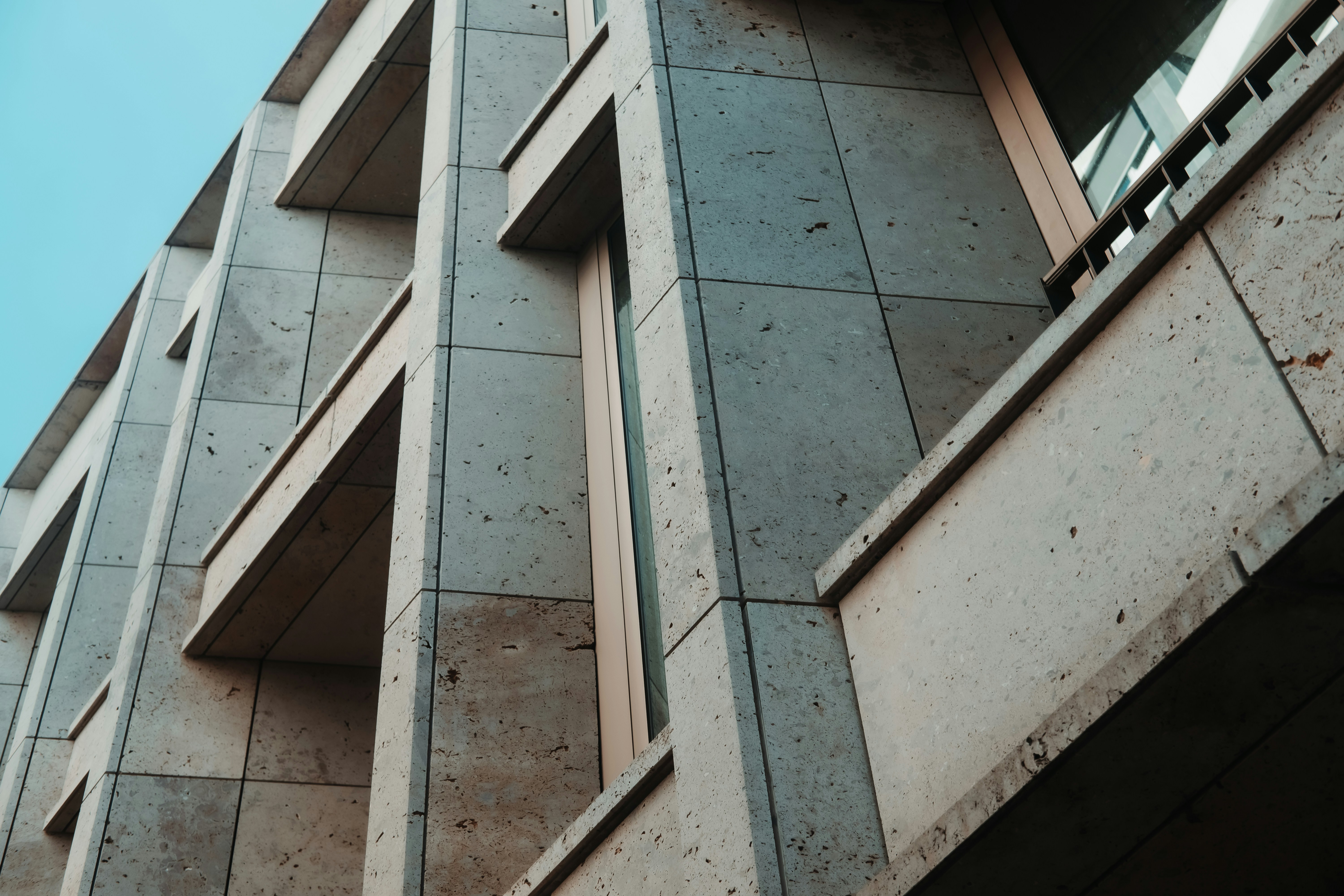 Abstract view of a contemporary building facade, emphasizing geometric patterns and textures of stone and glass.