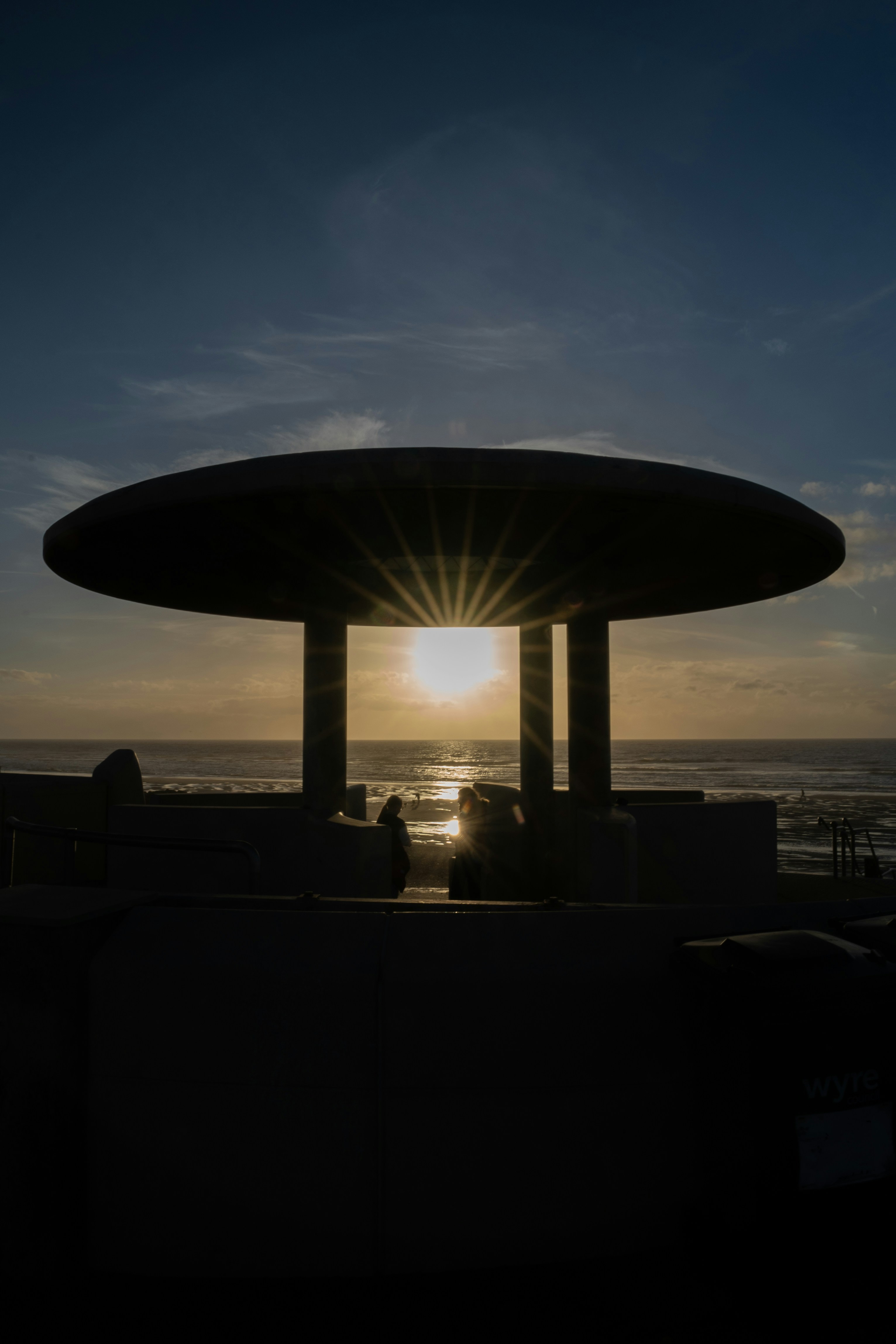 Sunburst Between Pillars: Dusk at the Circular Canopy by the Sea