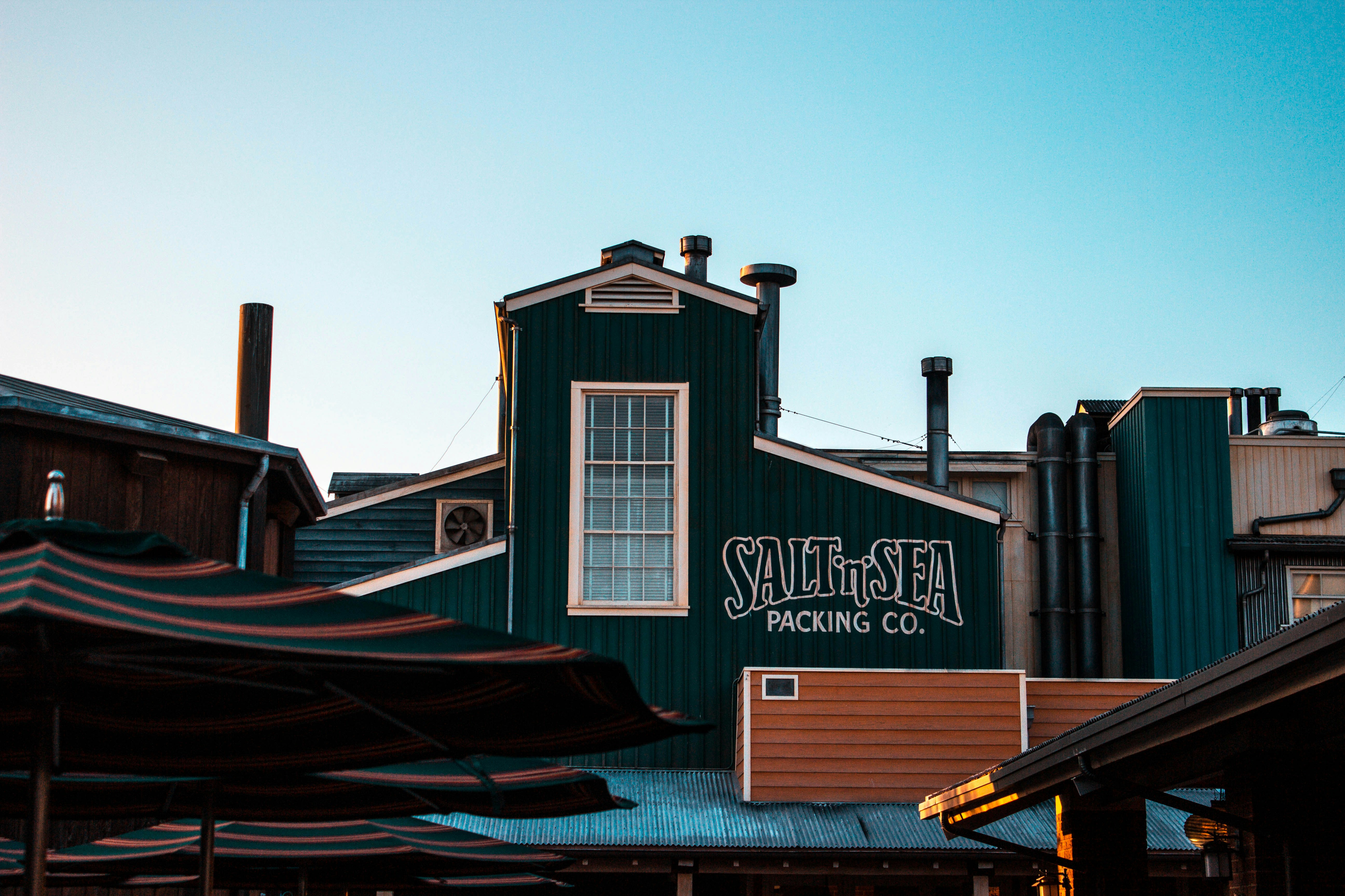 Teal Facade of Salt & Sea Packing Co. Rising Against a Clear Blue Sky