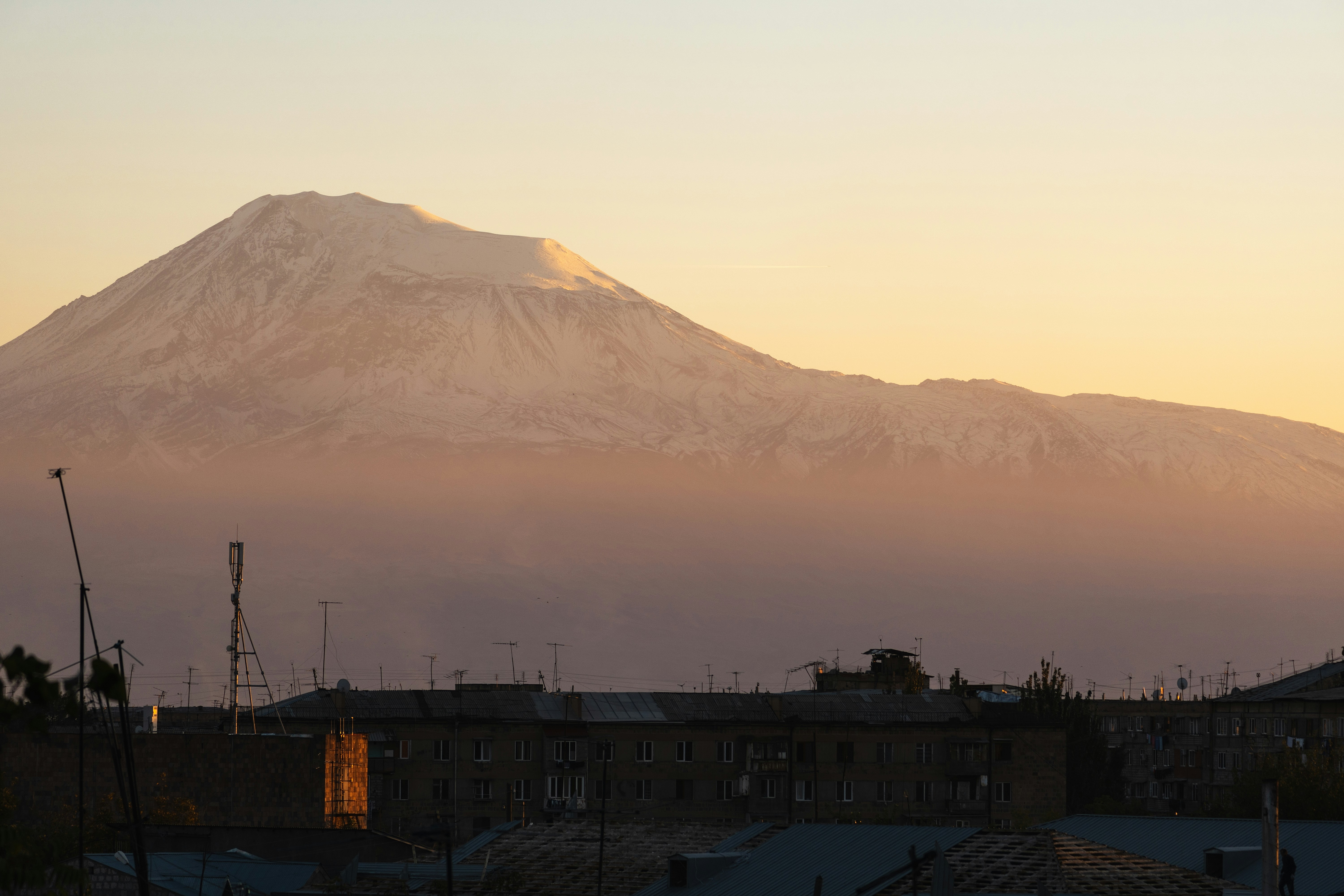 Snow-Capped Summit at First Light Over a Slumbering City