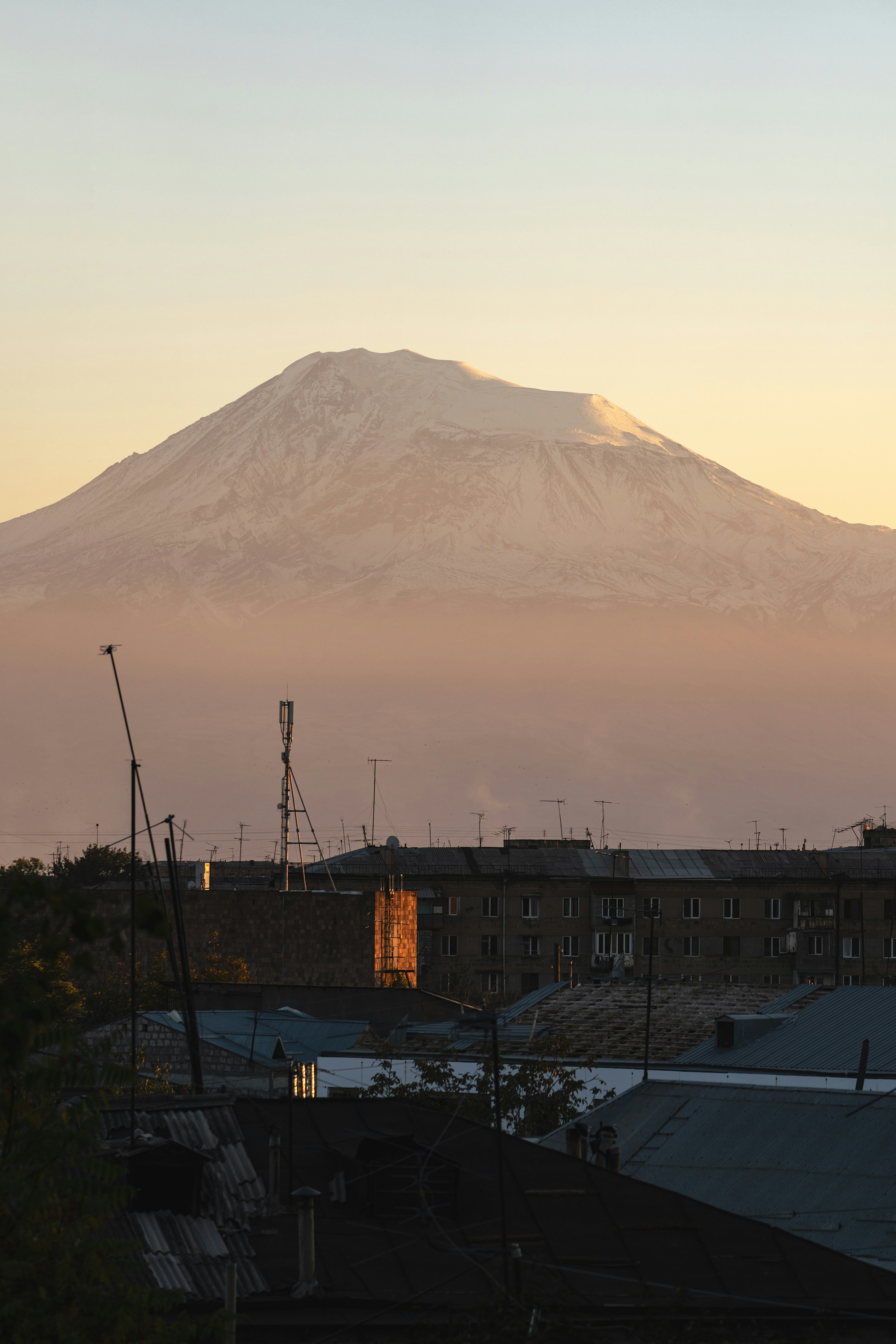 Alpenglow Over the City: Dawn-Lit Snow-Capped Summit Above Rooftops