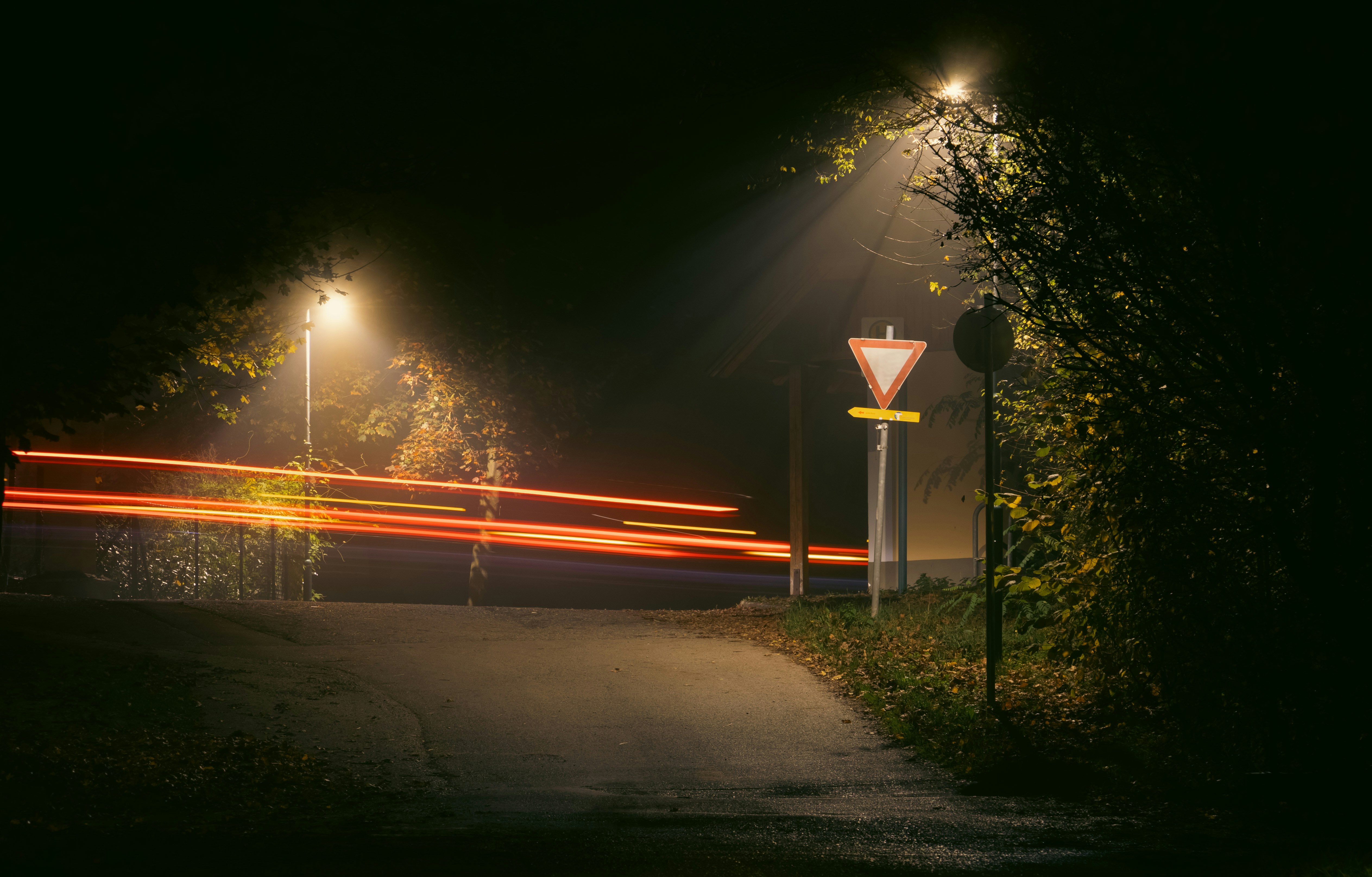 A road with a sign and street lights at night photo – Free Lighting ...