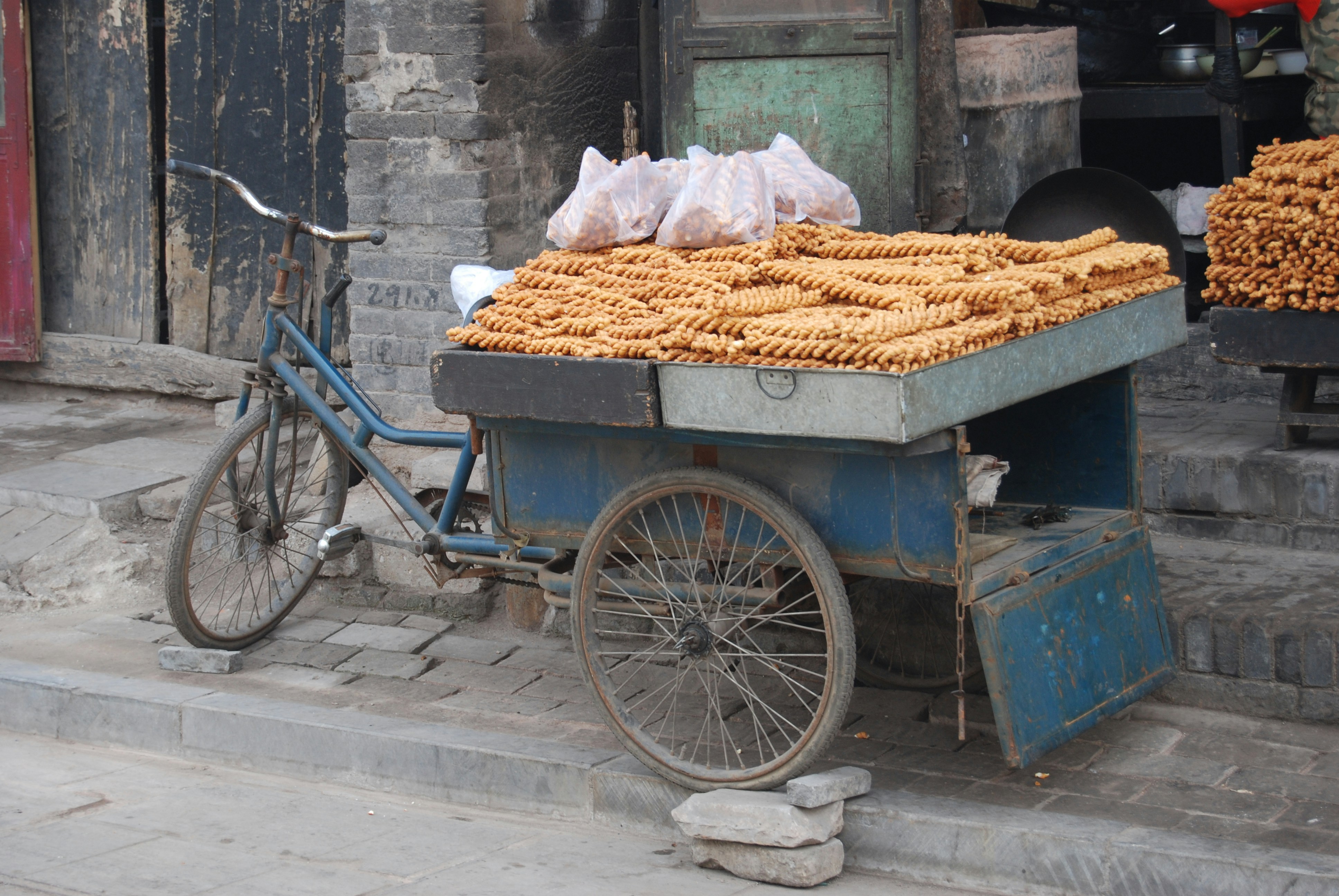 Blue Street Cart Brimming with Golden Snacks Under a Weathered Facade