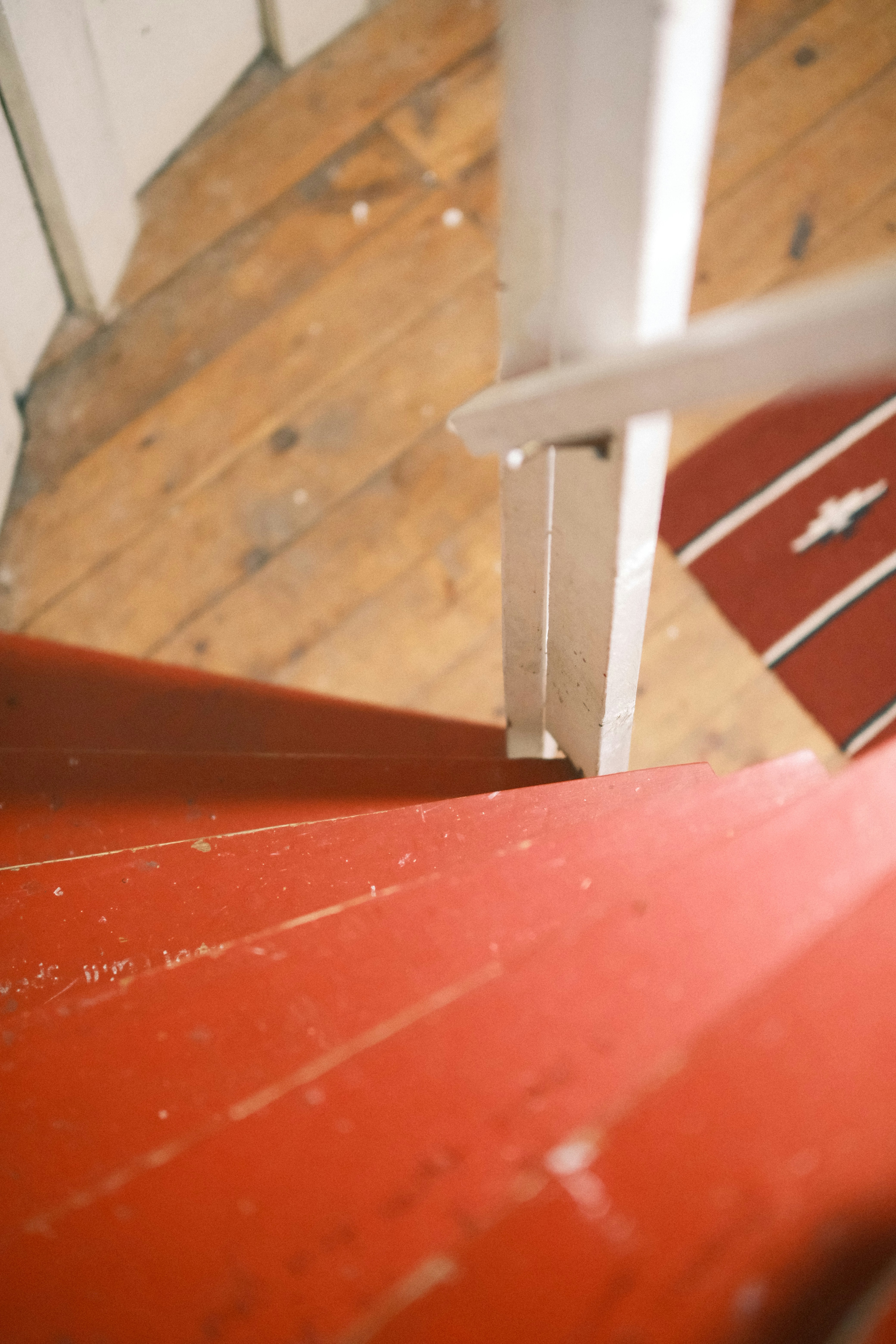 Crimson Staircase Descends into Warm Wood and White Rail