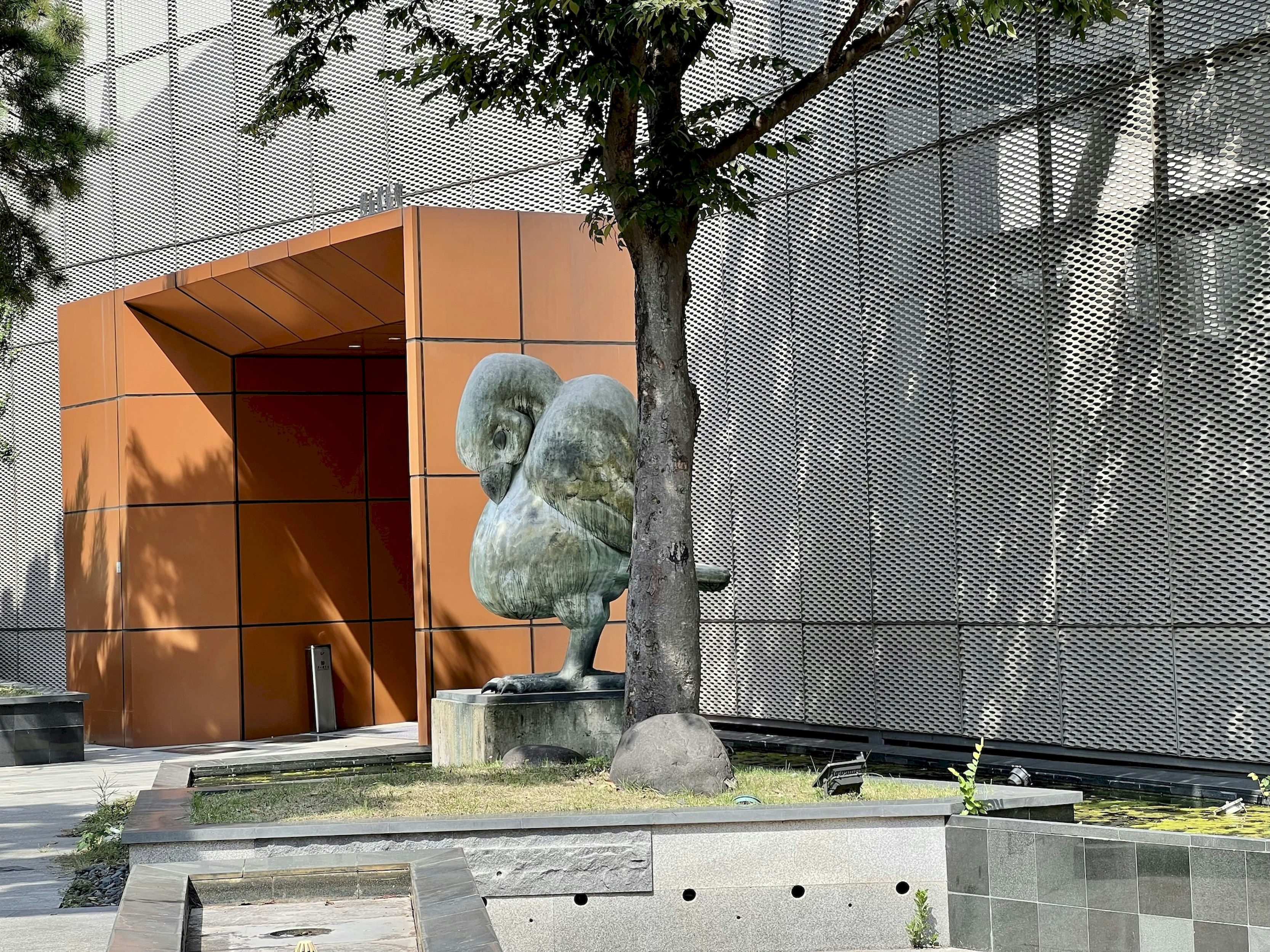 Stone Ram at the Orange Threshold: Quiet Geometry of a Modern Courtyard