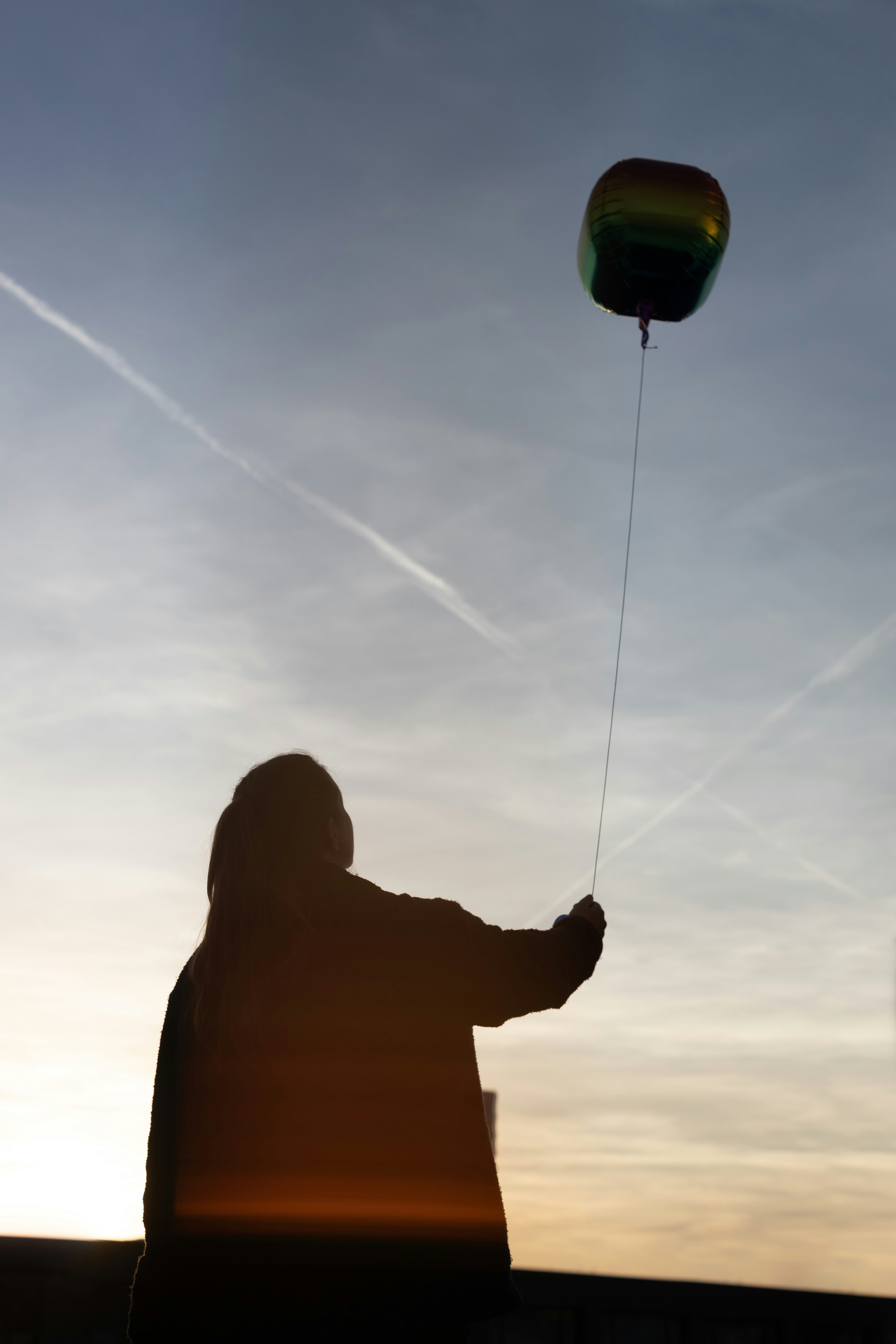 Dusk Silhouette: A Rainbow Parachute Lifted by the Wind