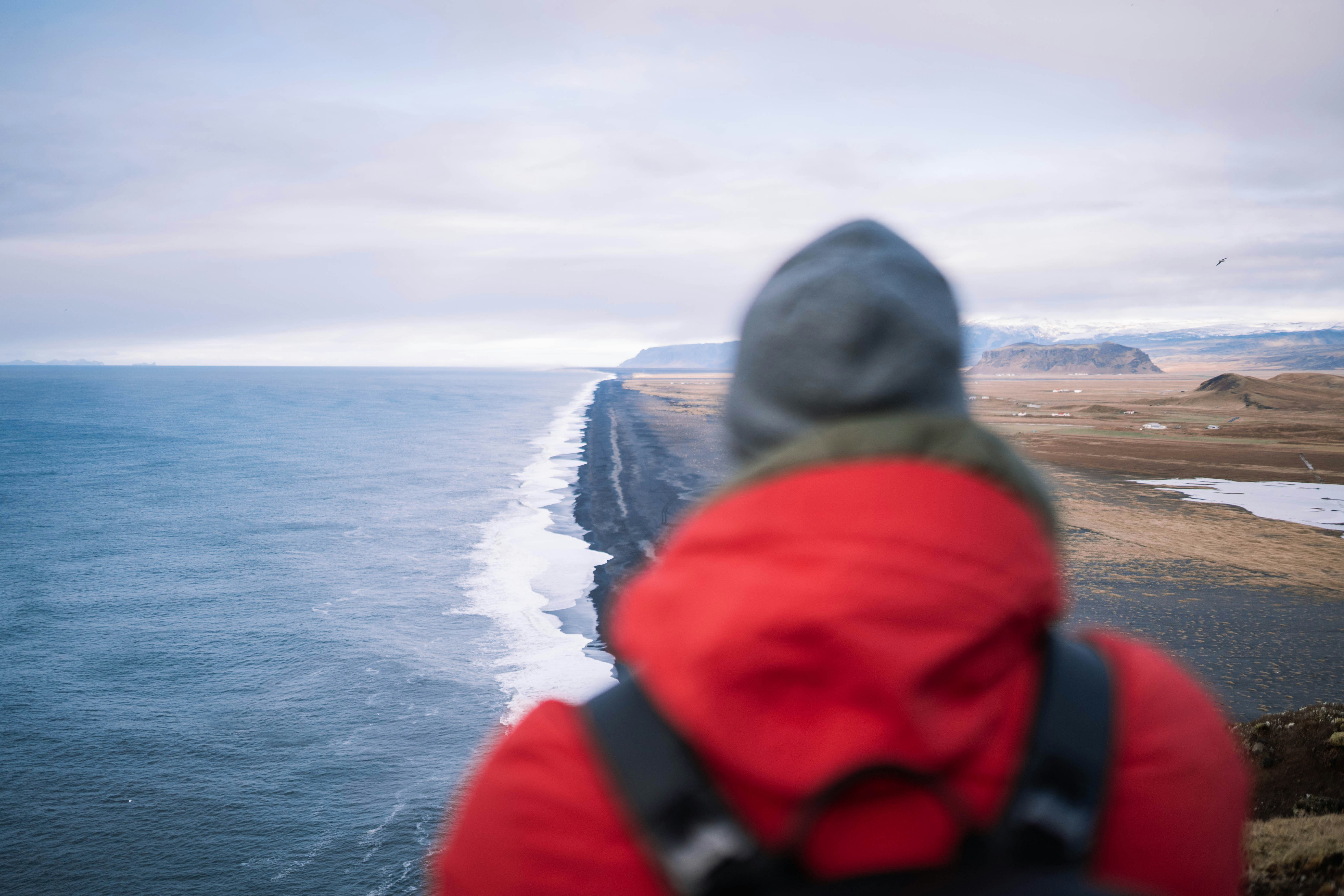 Red-Jacket Foreground Overlooking a Rugged Coastal Cliffs