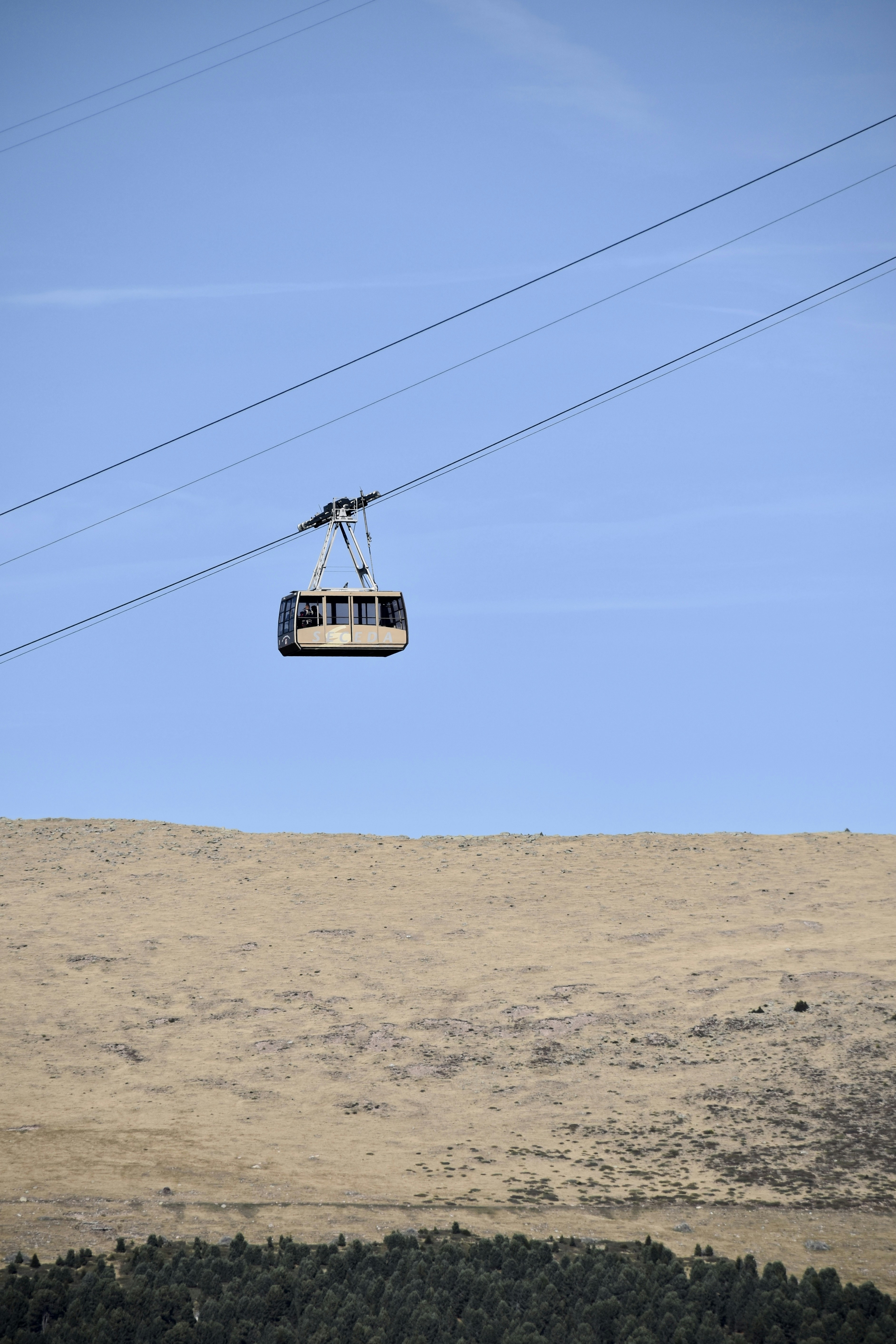 Solitary Gondola Over a Quiet Desert Ridge Under a Pristine Blue Sky