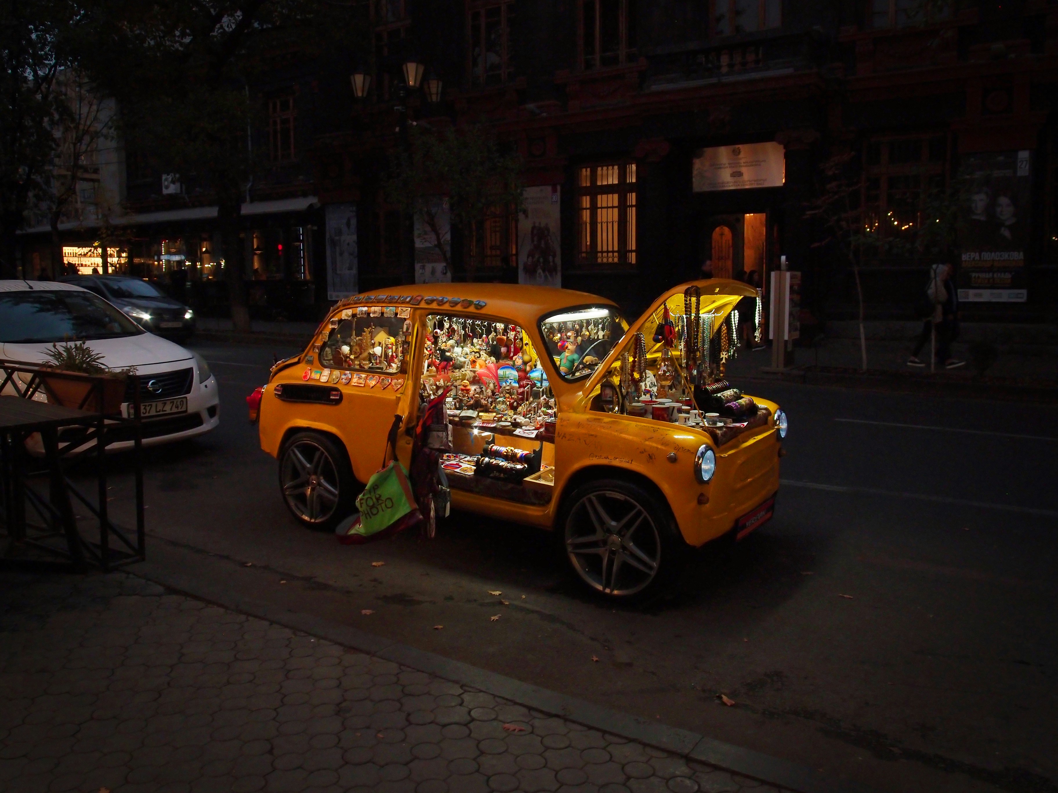 Yellow Microcar Night Market: a lantern-lit street stall inside a compact taxi