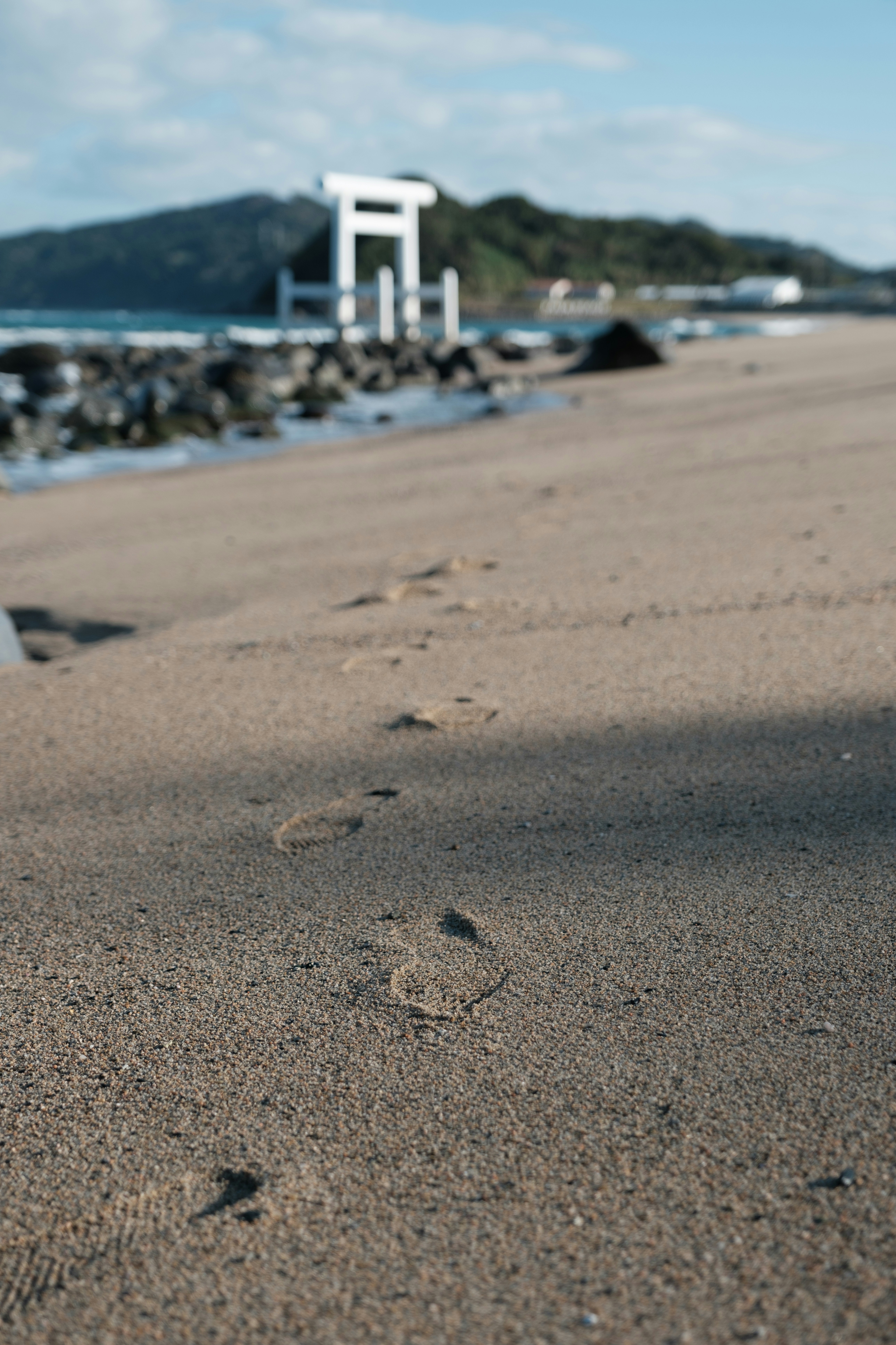 Footprints Toward a Distant Gate on a Quiet Beach