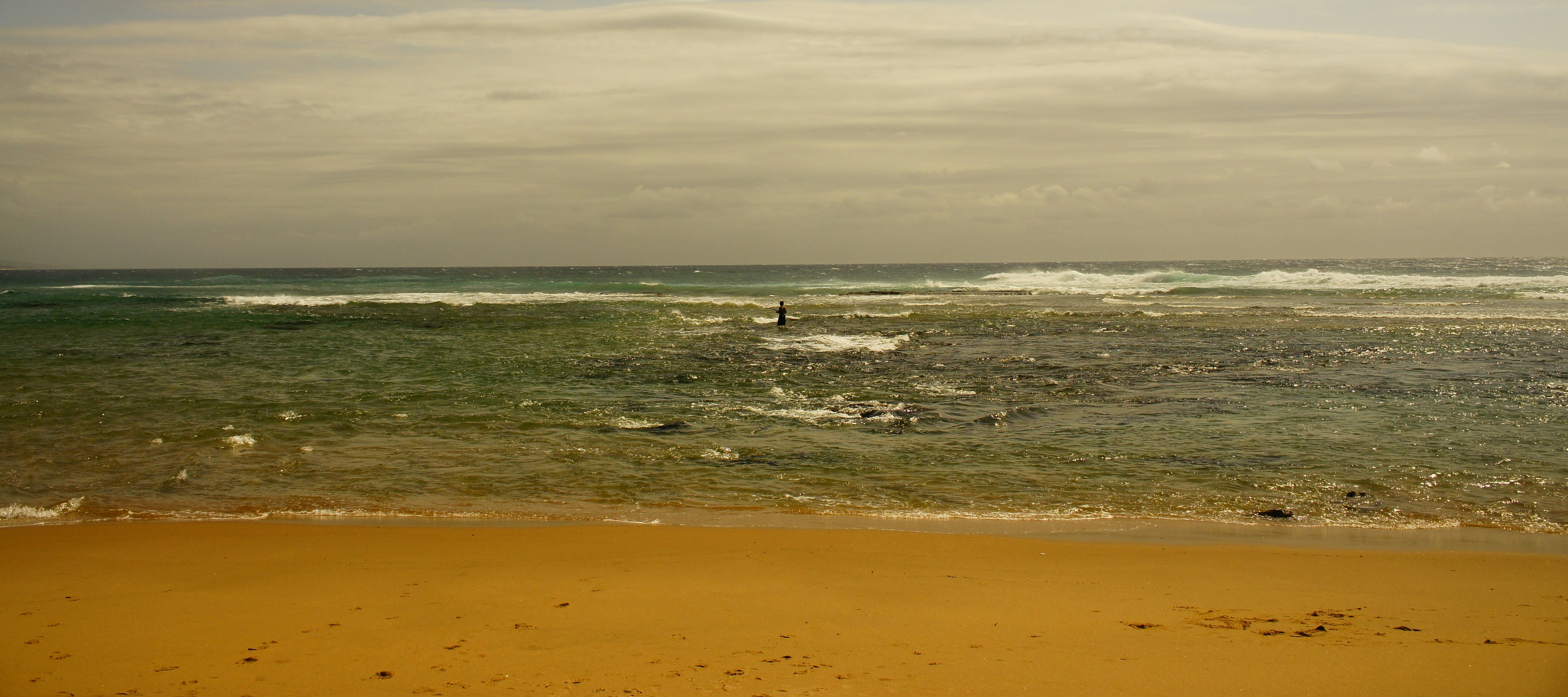 Lone Figure Between Amber Shore and Green-Blue Tide