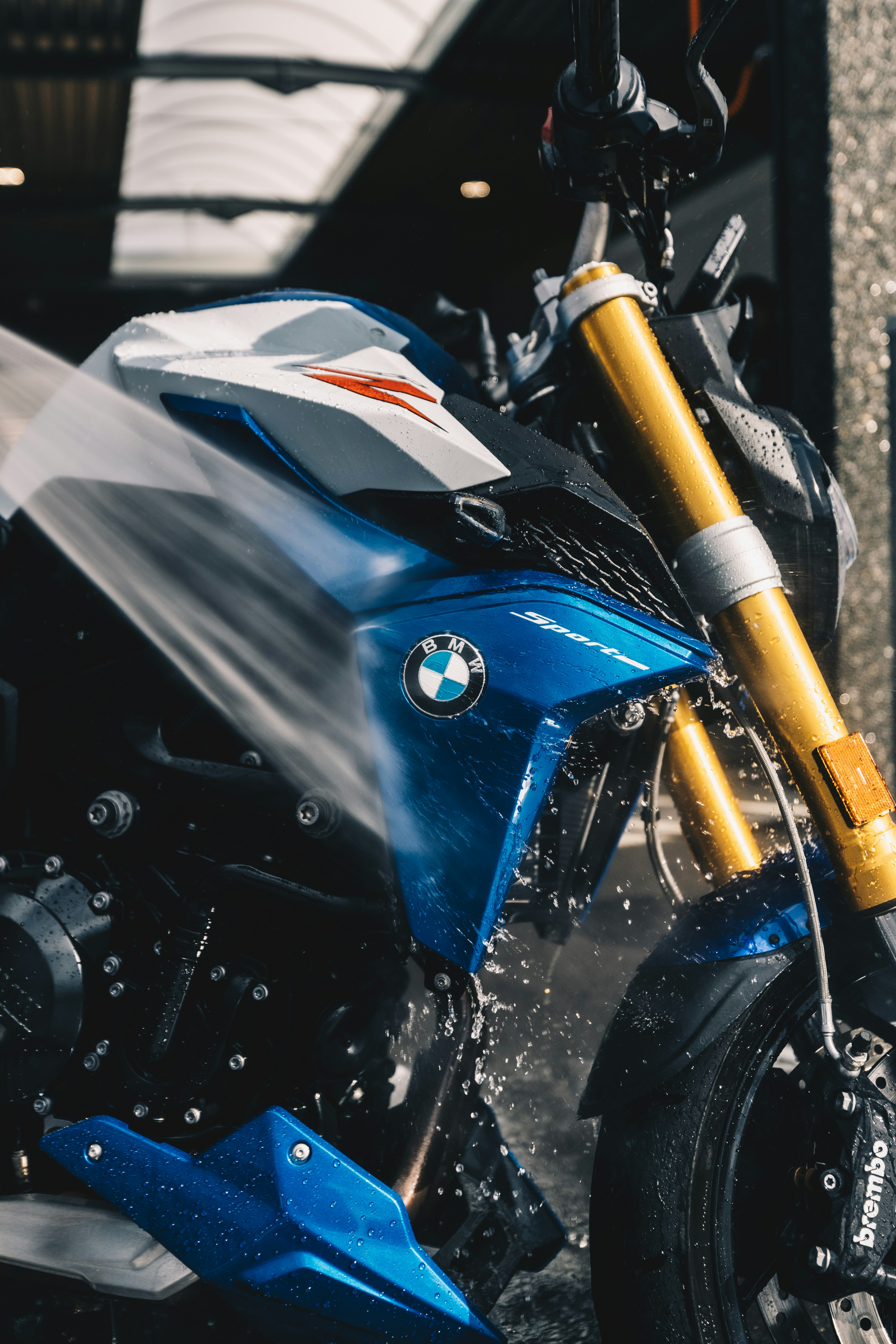 Rain-Kissed Blue BMW: Close-Up of a Sportbike's Front Fairing and Gold Forks