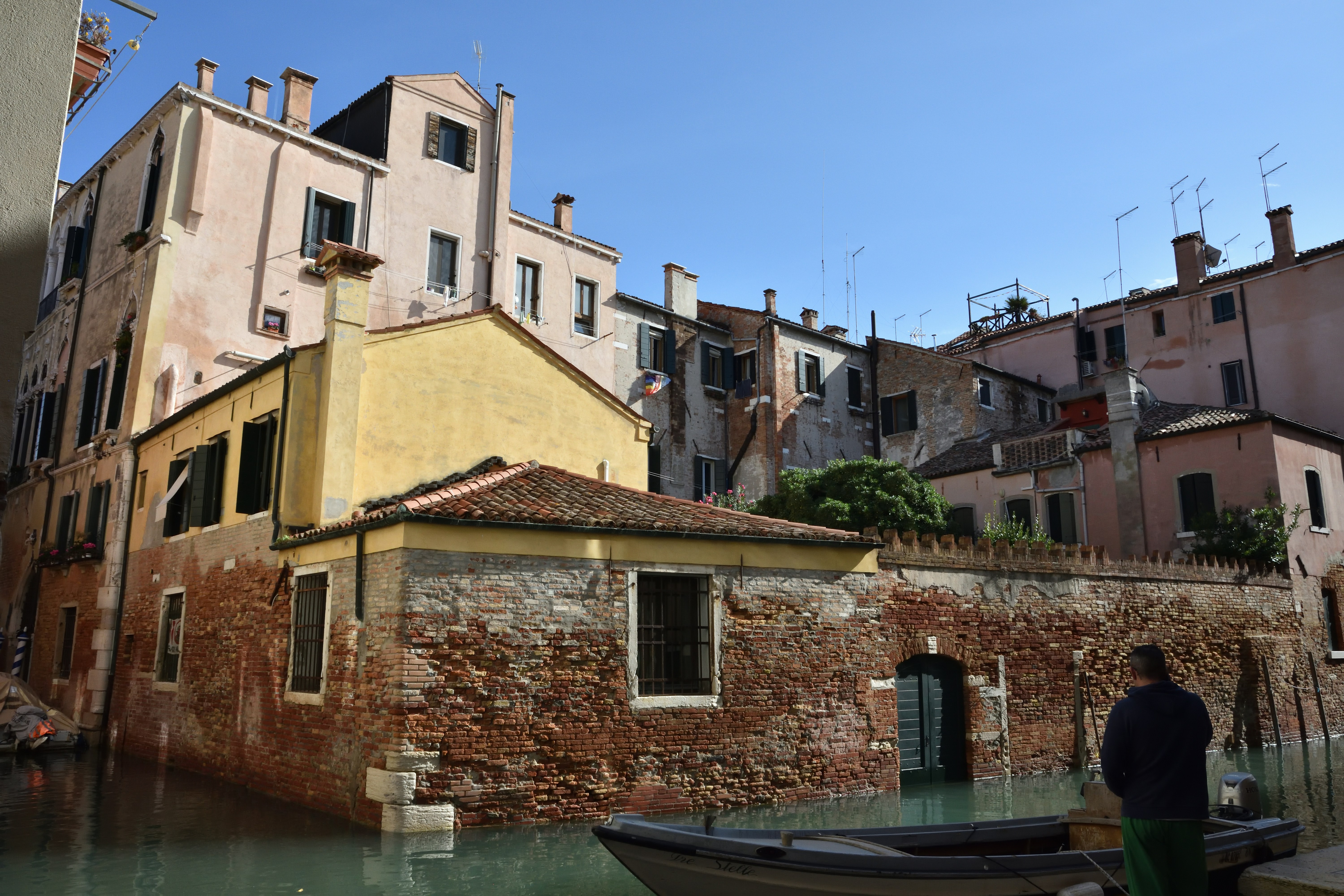 a person standing on a boat in a canal with buildings on either side