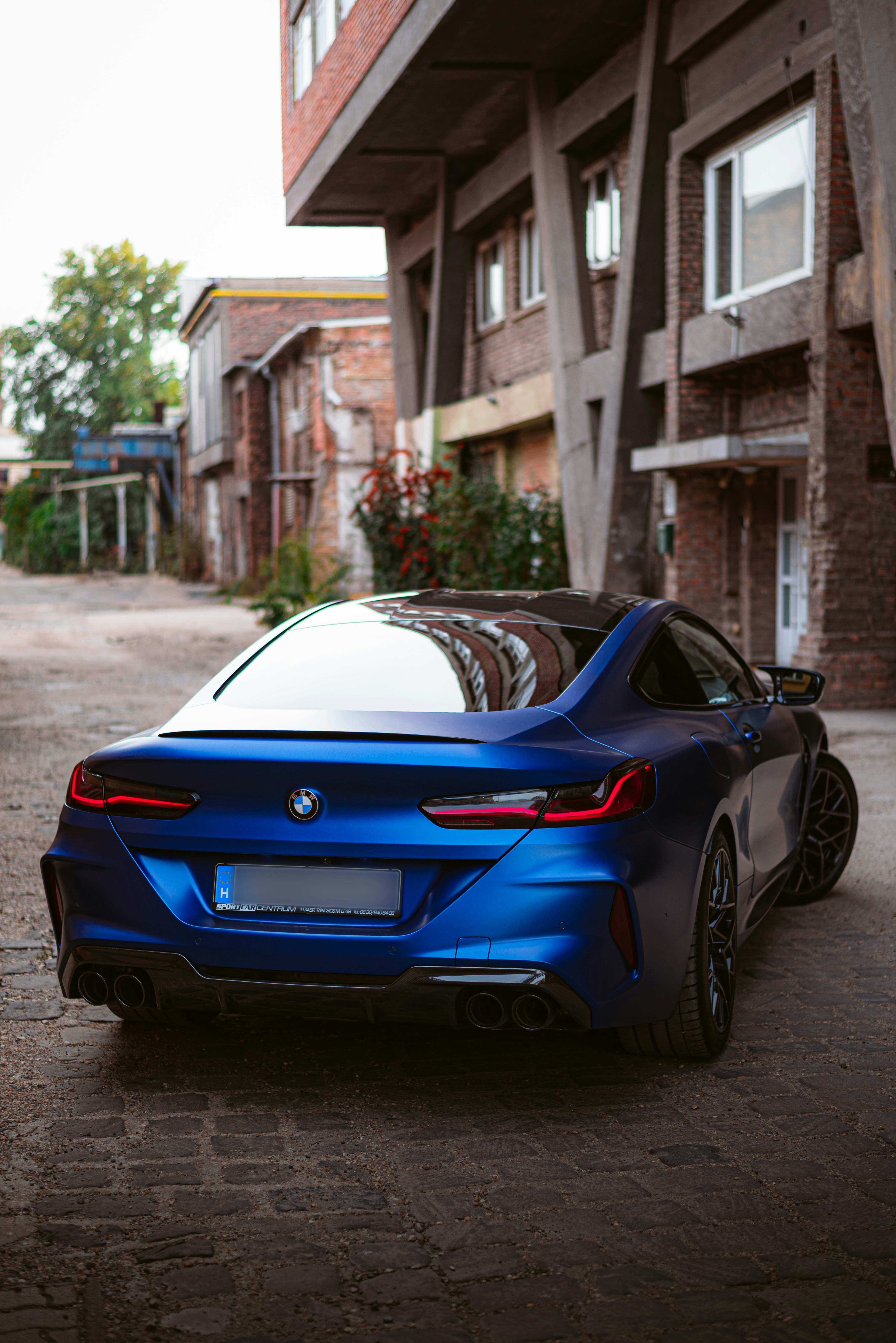 A blue sports car parked in front of a brick building photo – Free ...