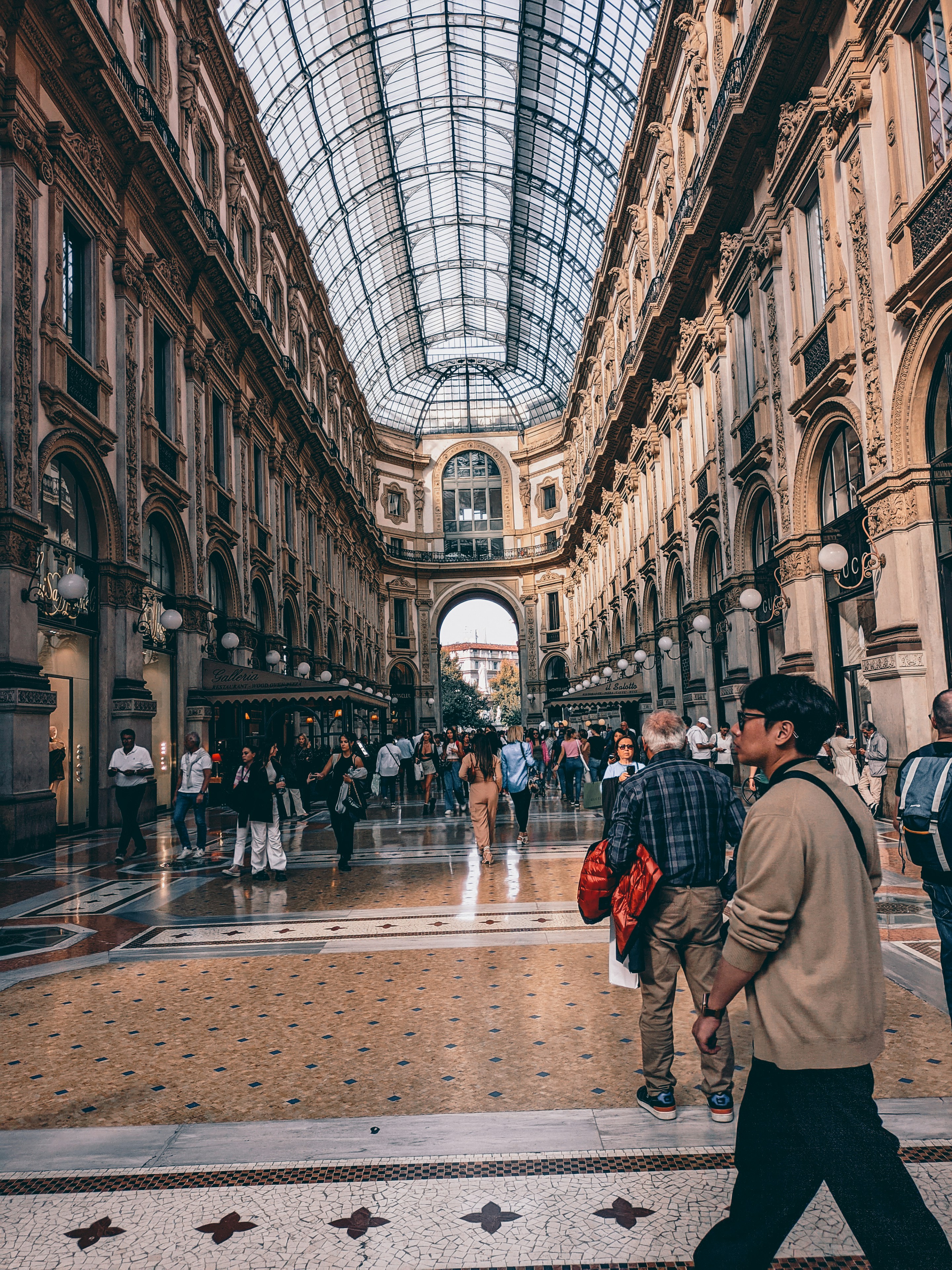 people walking on a street with Galleria Vittorio Emanuele II in the background