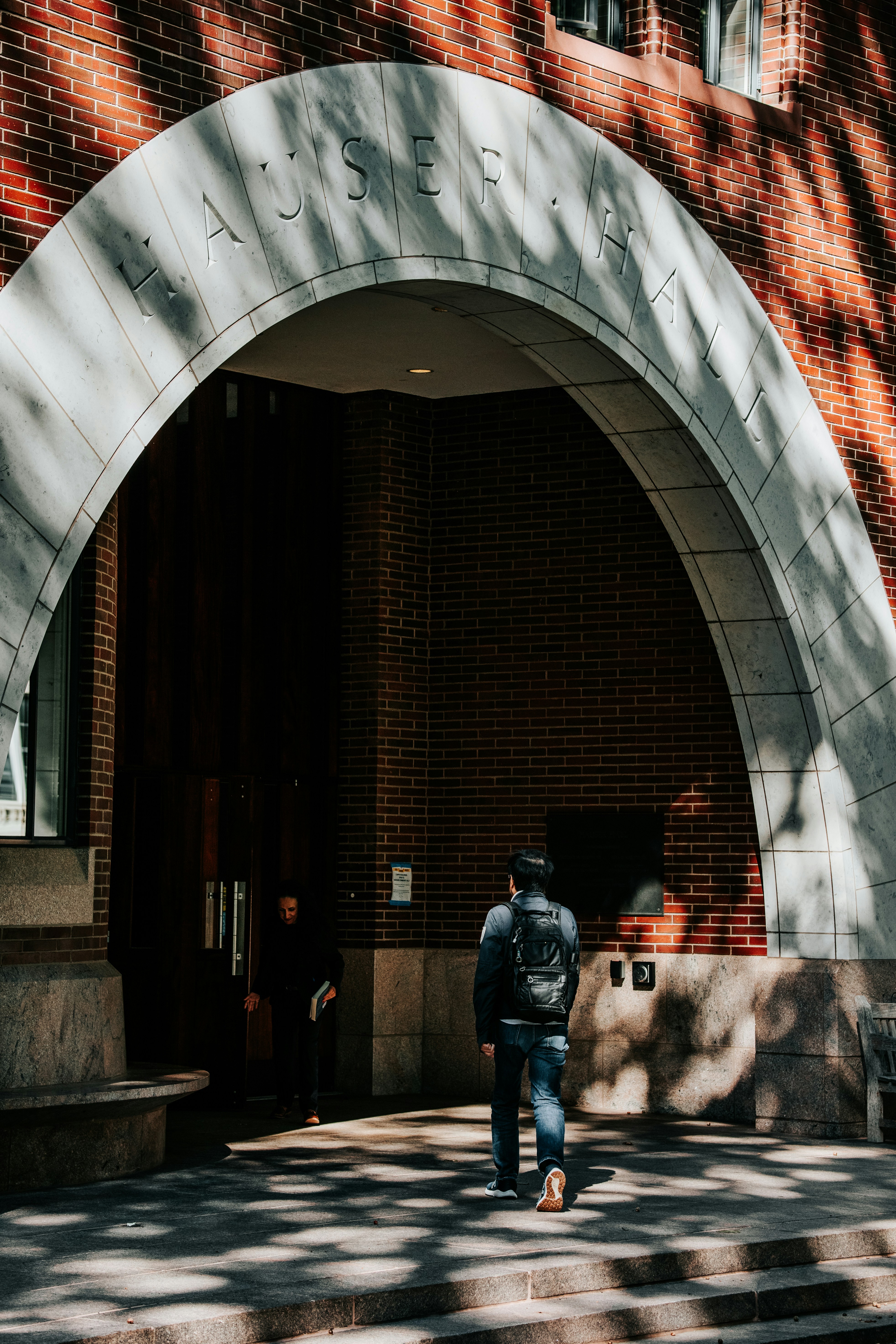 Approaching the Arch: A man walks toward a brick doorway under a sun-dappled arch