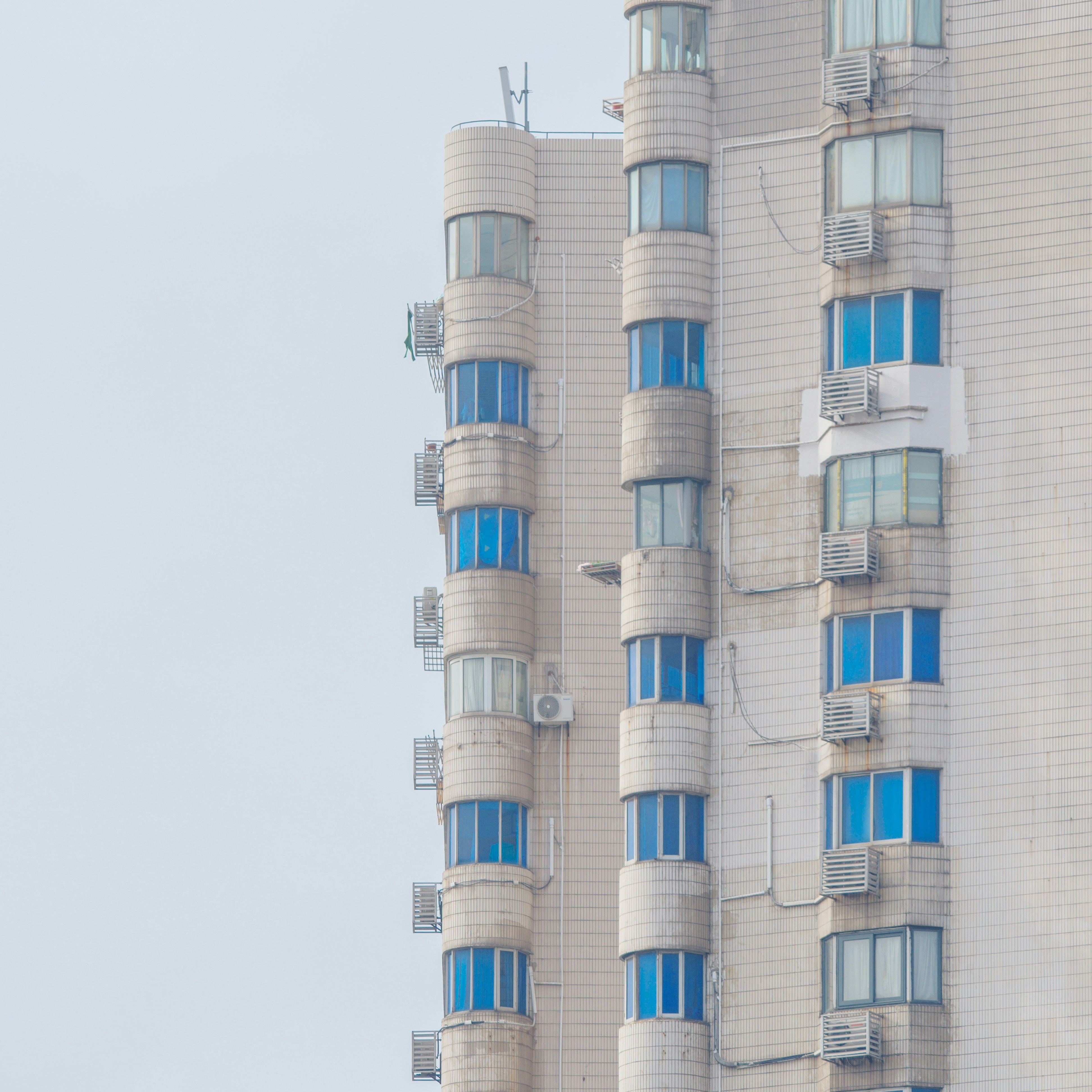 Close-up view of a modern building facade showcasing a pattern of blue windows and air conditioning units. The architectural lines create a rhythmic visual experience.