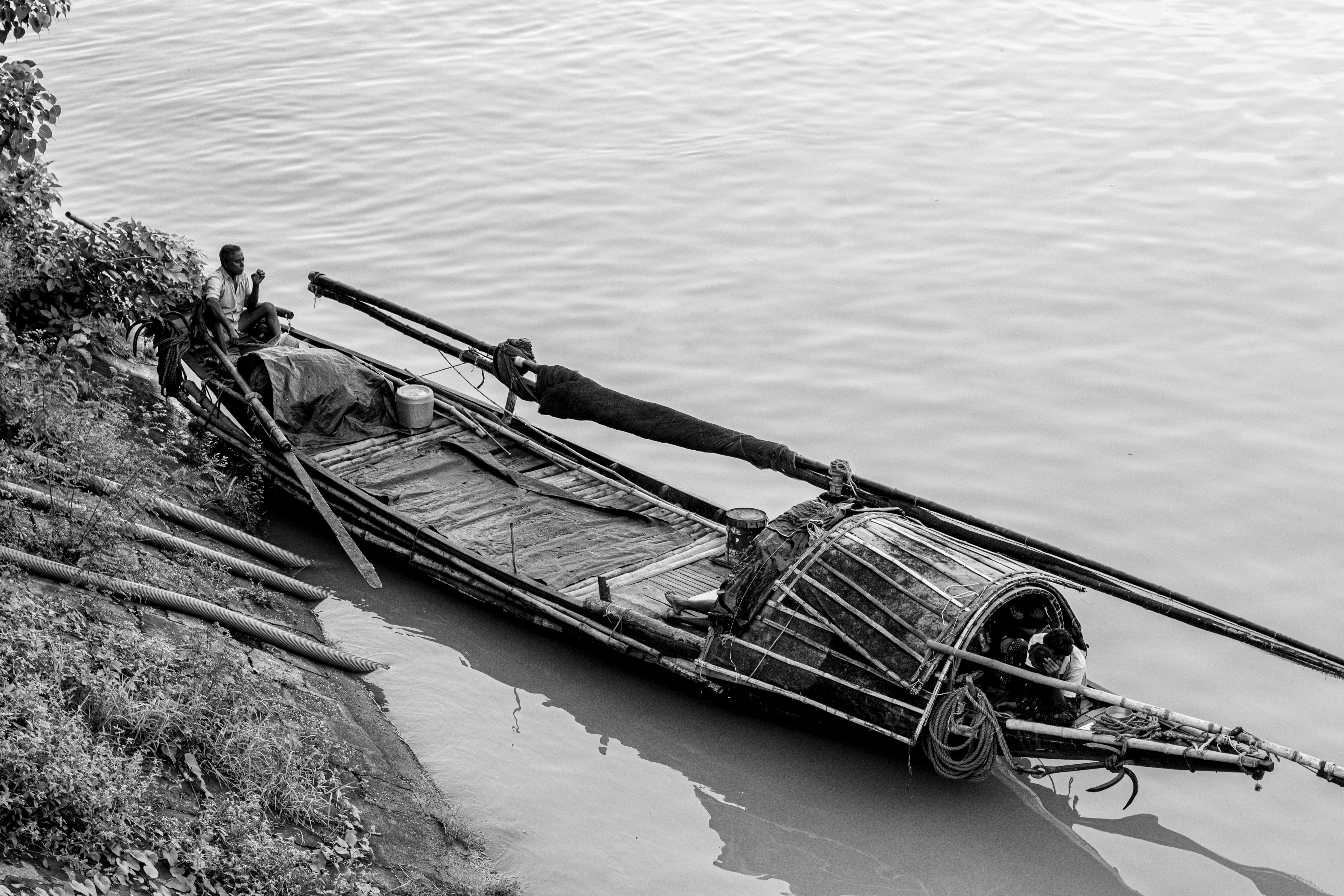 Wooden boat moored along a tranquil riverside with lush foliage nearby.