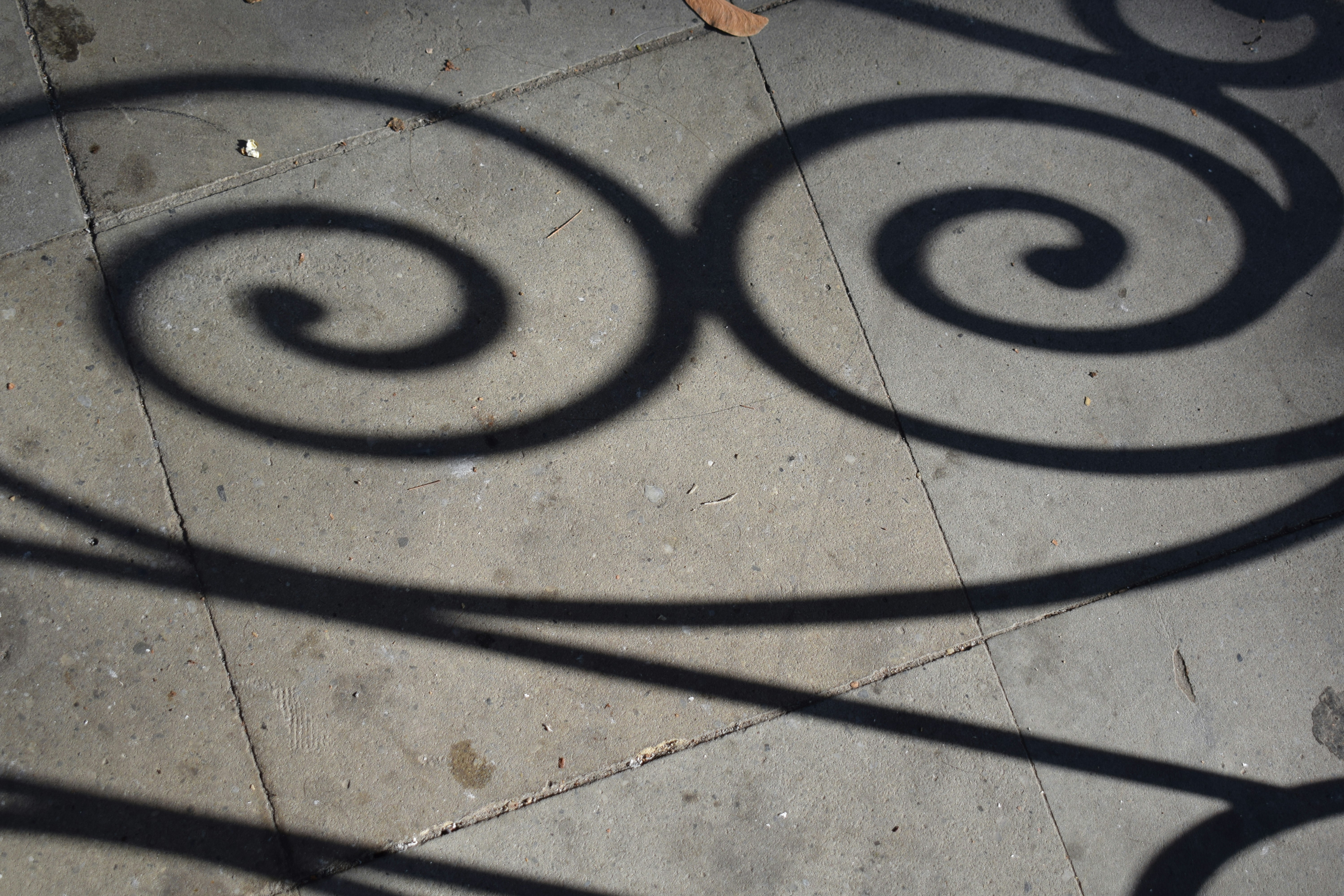Shadow Spirals: Ironwork Echoes on Sunlit Concrete