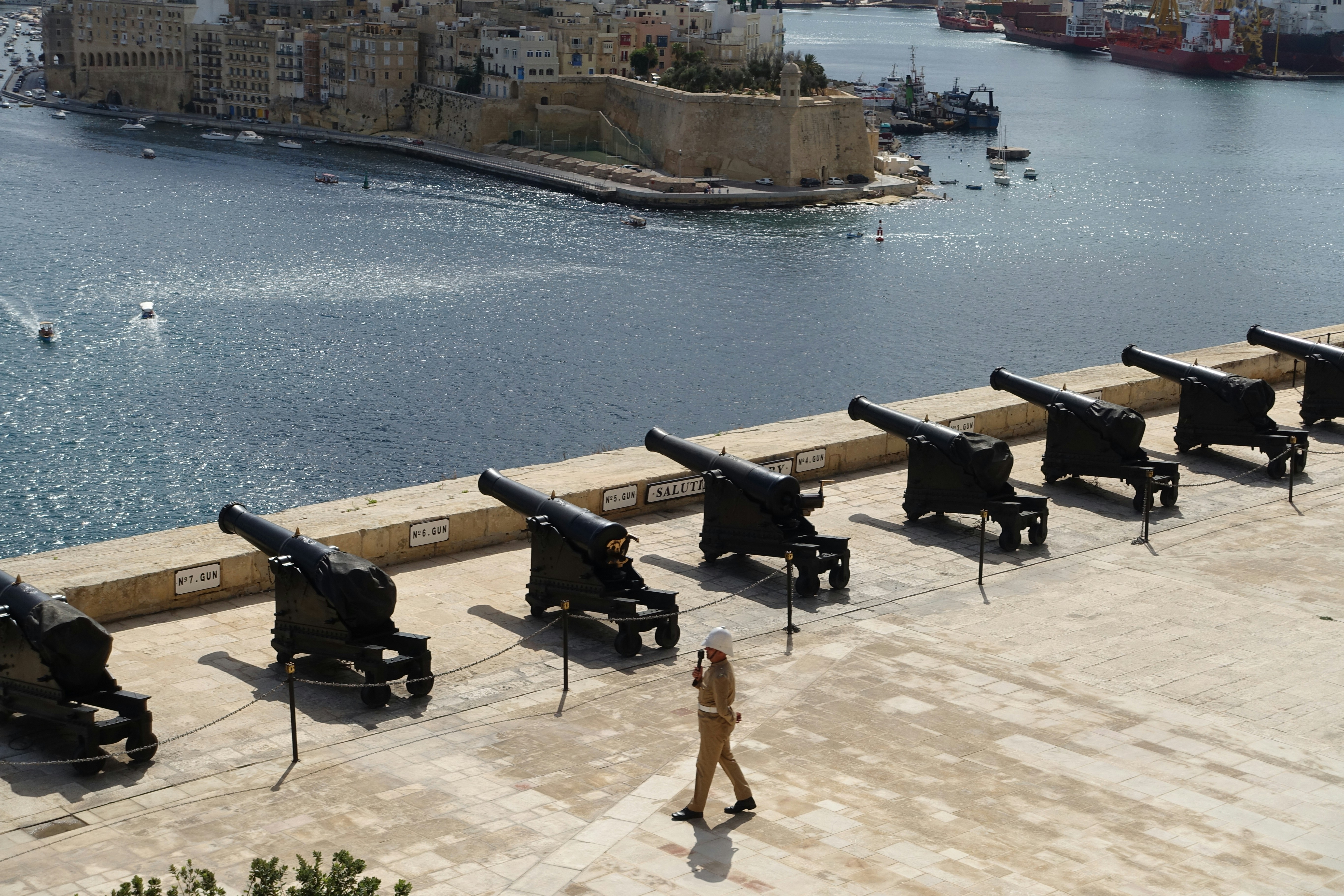 A person standing next to a row of cannons on a dock photo – Free ...