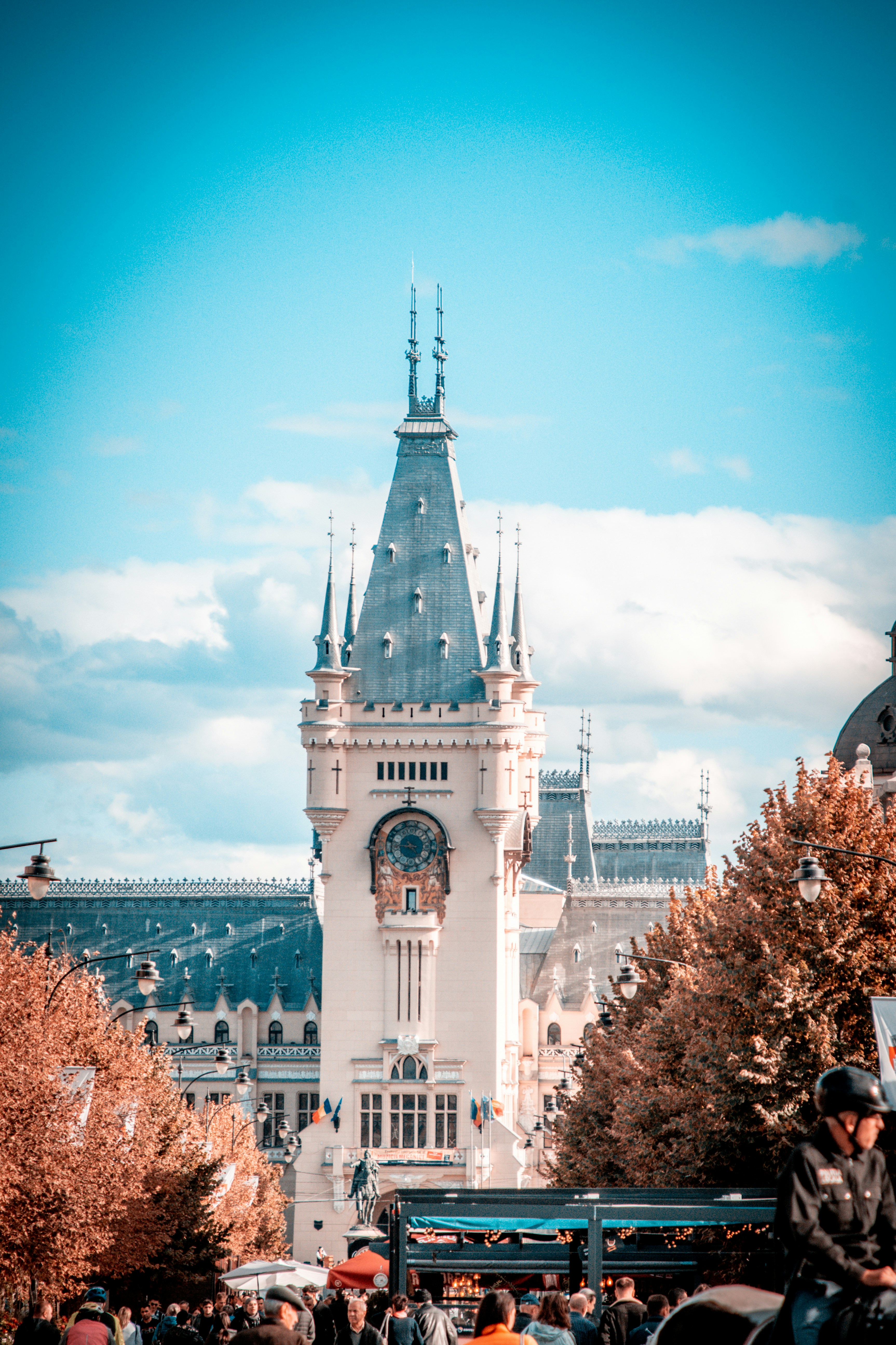 Spire in the Sun: A European Castle Square Framed by Autumn Trees