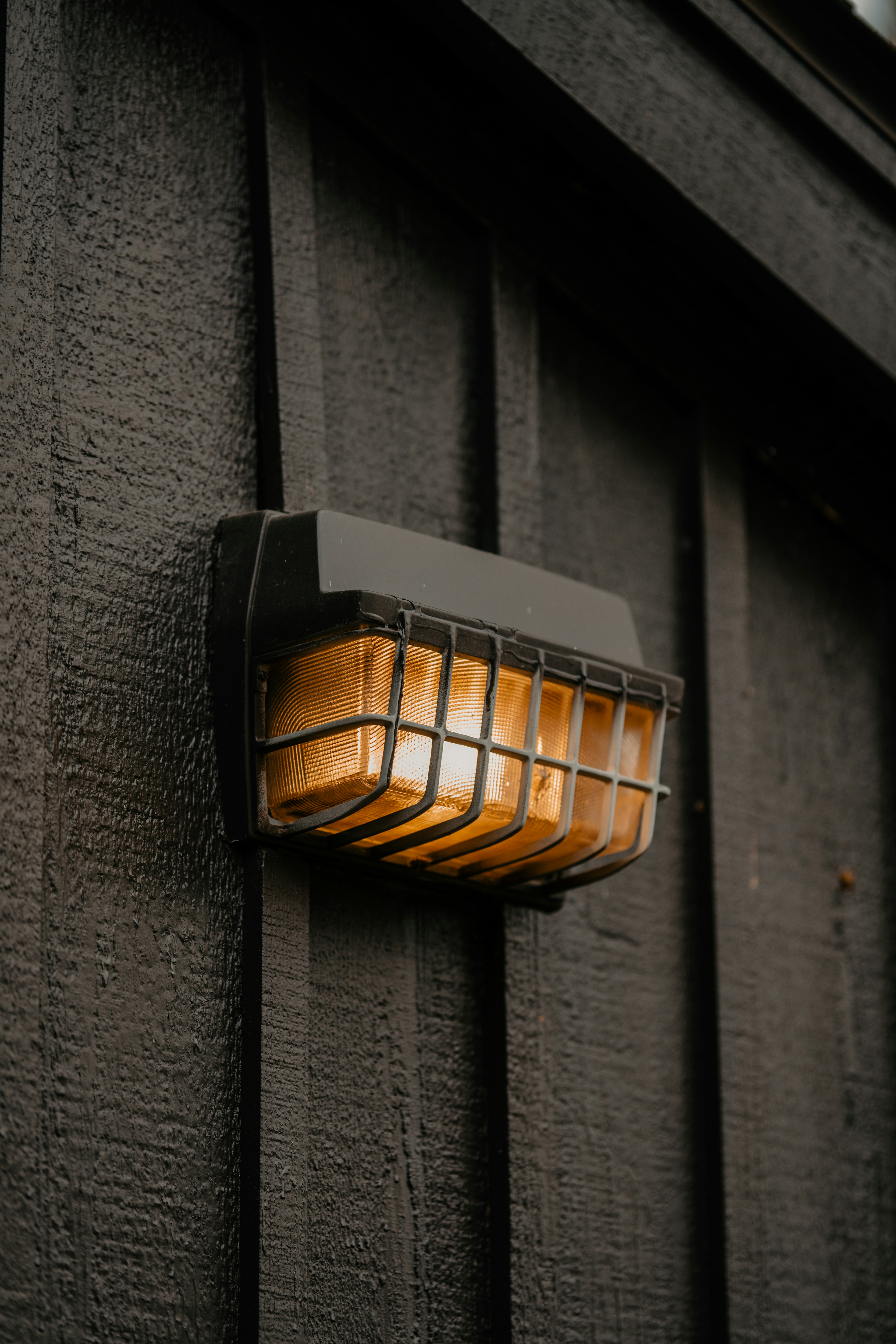 Industrial Glow: A Night-Lit Wall Lantern on Charred Timber