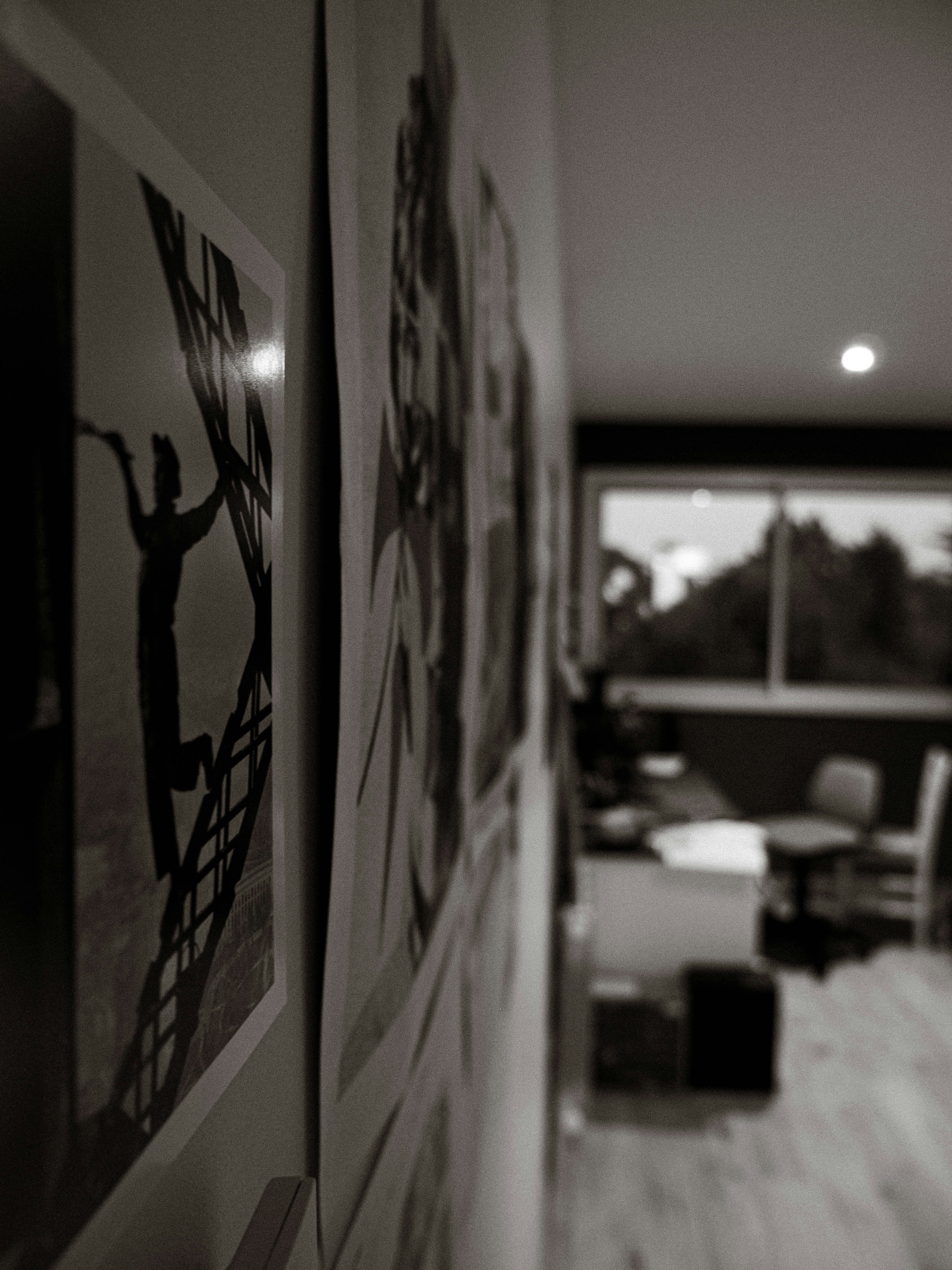 Black and white photographs line the wall, leading the viewer's gaze towards a softly lit workspace in the background. The composition invites exploration of artistic expression.